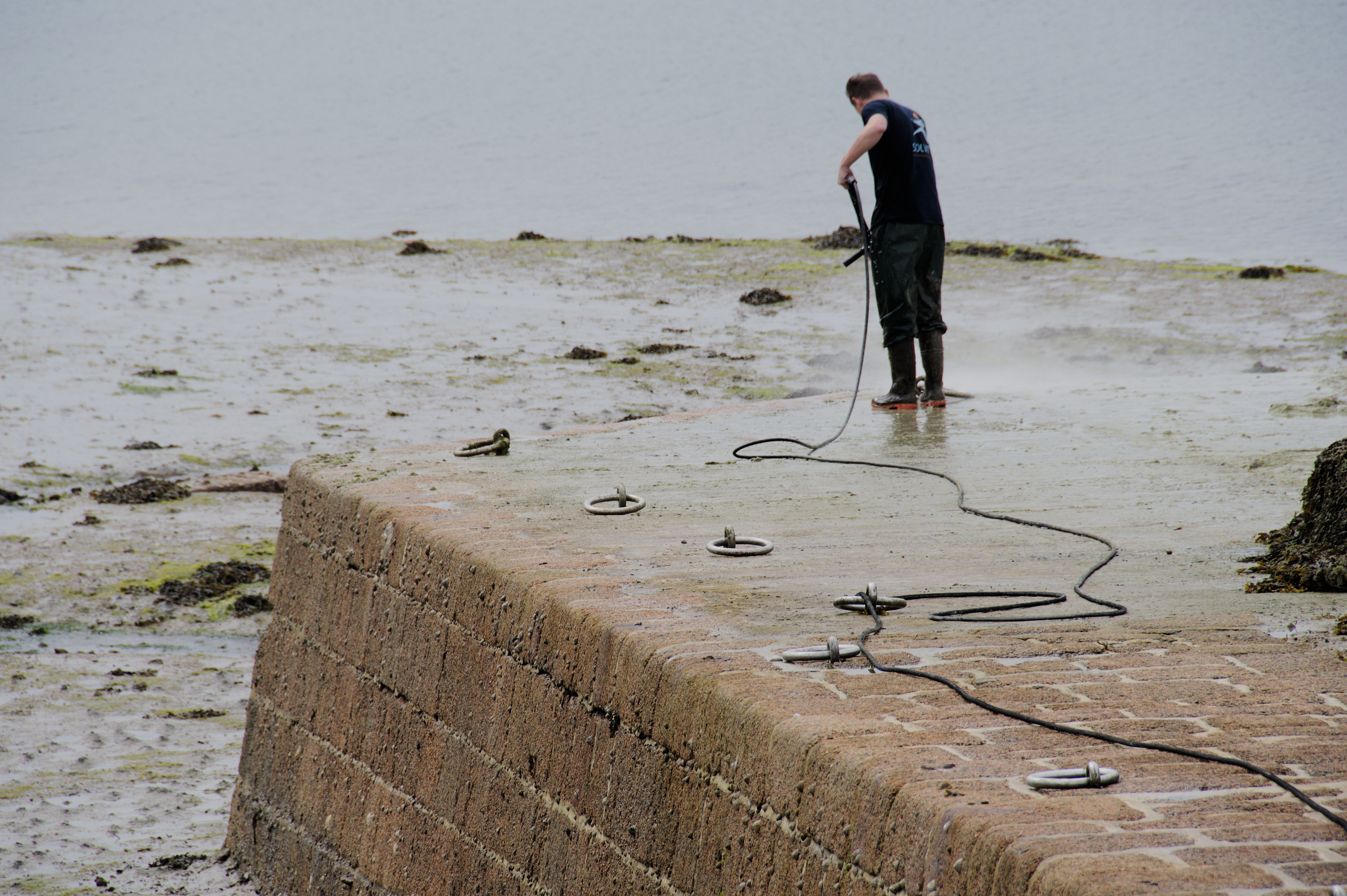 Man with Hose on Pier near Sea after Storm · Free Stock Photo