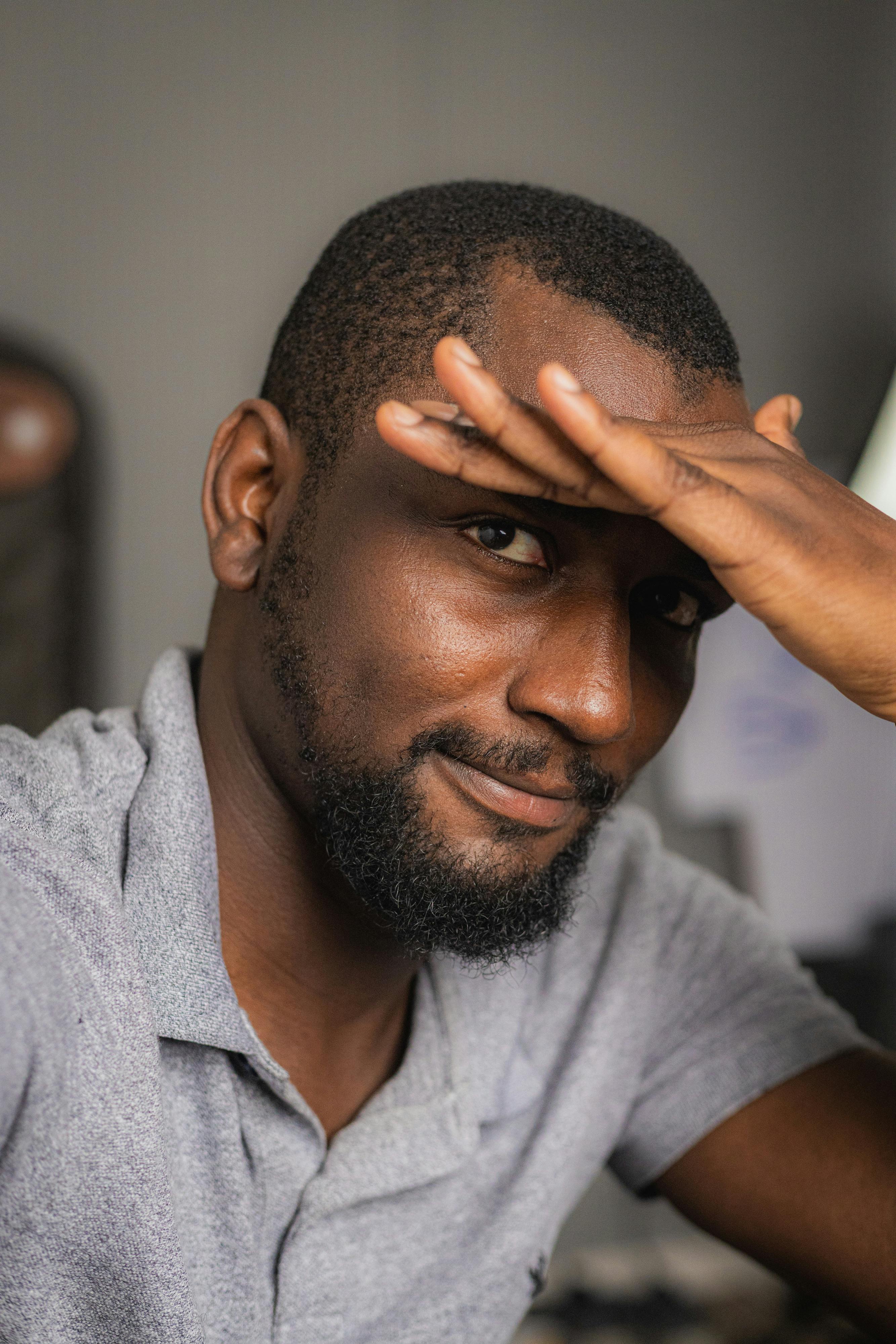 Smiling Man with Hand on Forehead · Free Stock Photo
