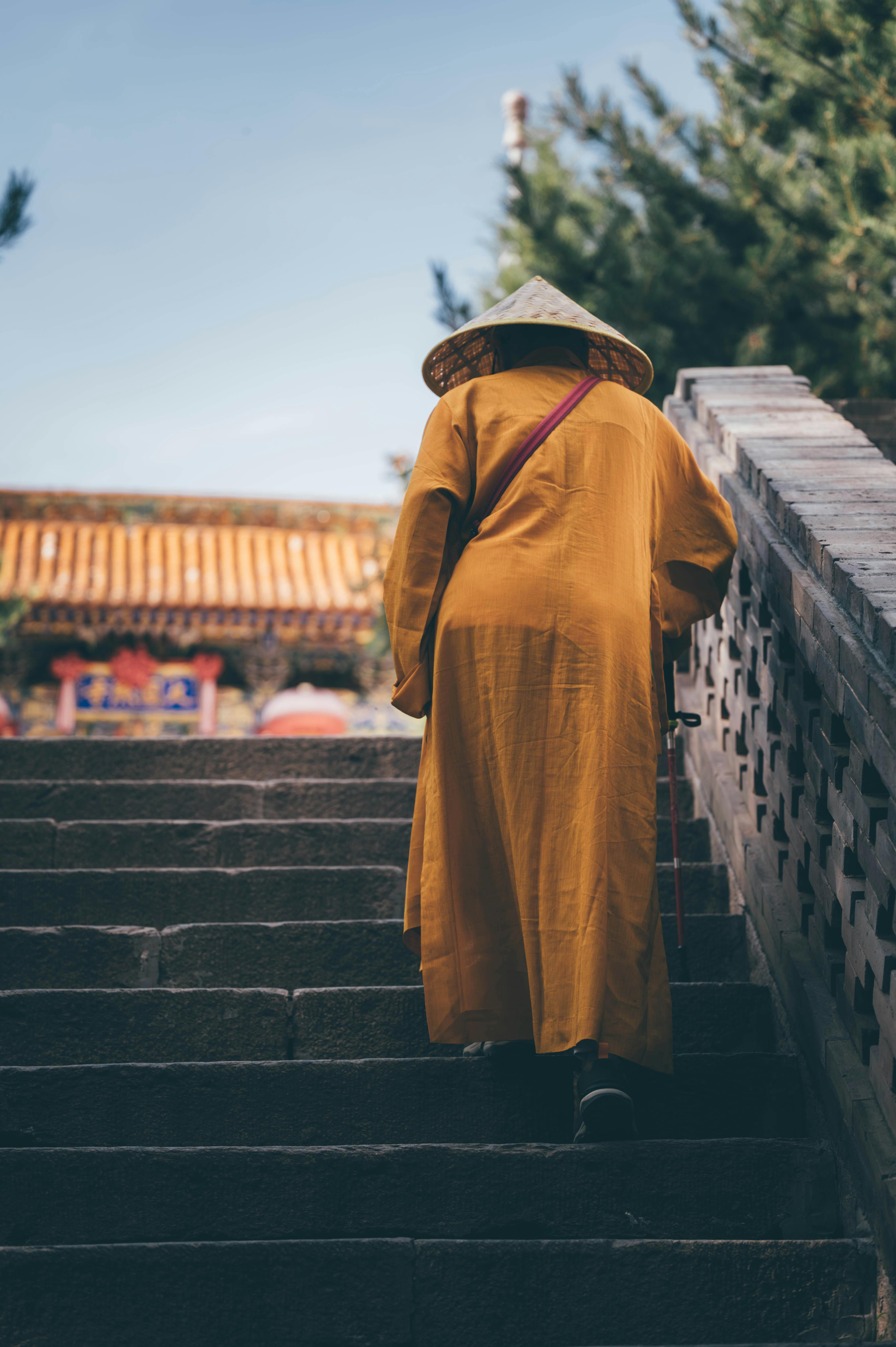 Back View of a Person in a Gown and a Conical Hat Walking up the Stairs ...