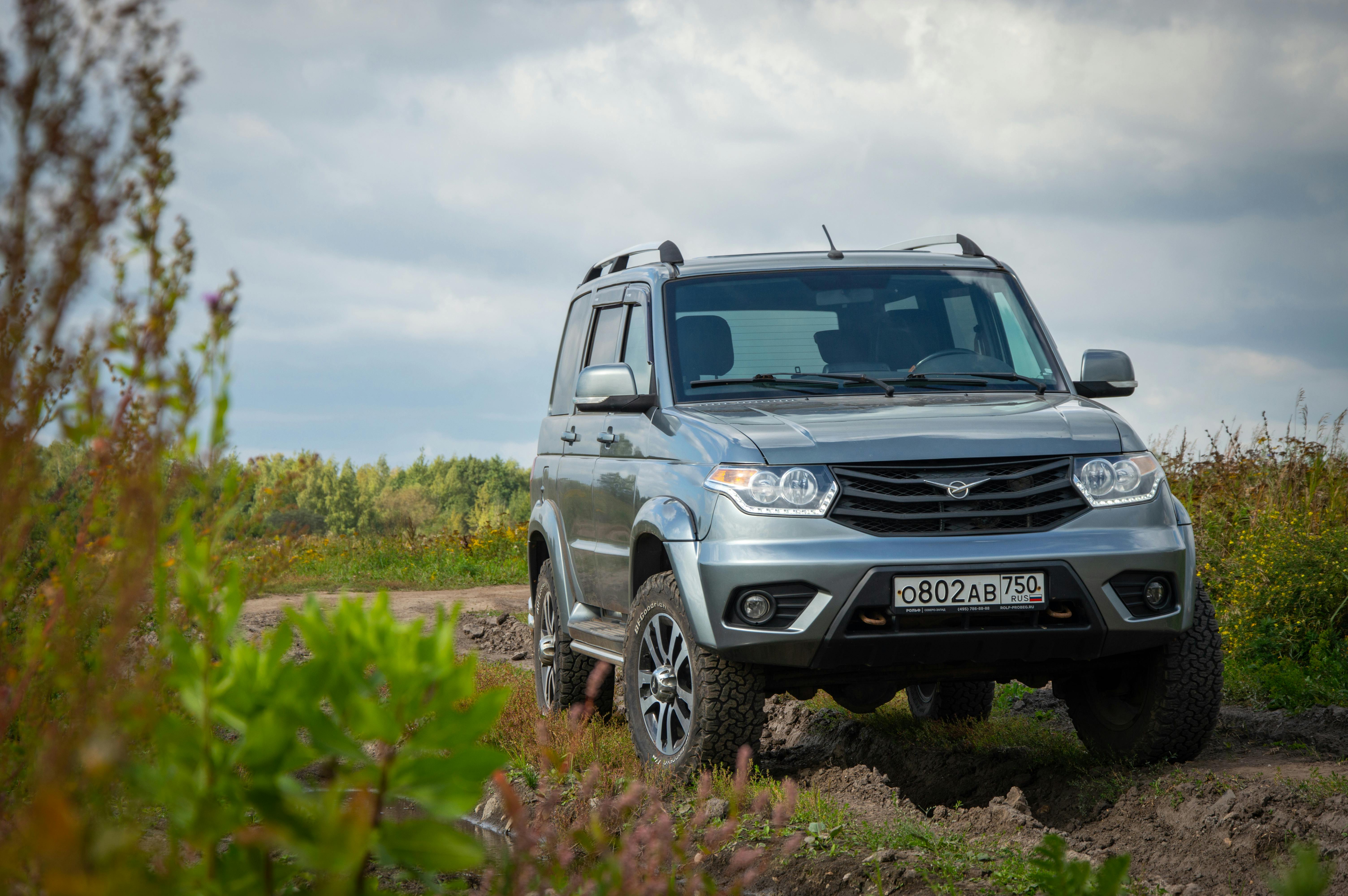 Silver UAZ Patriot on Road with Forest behind · Free Stock Photo