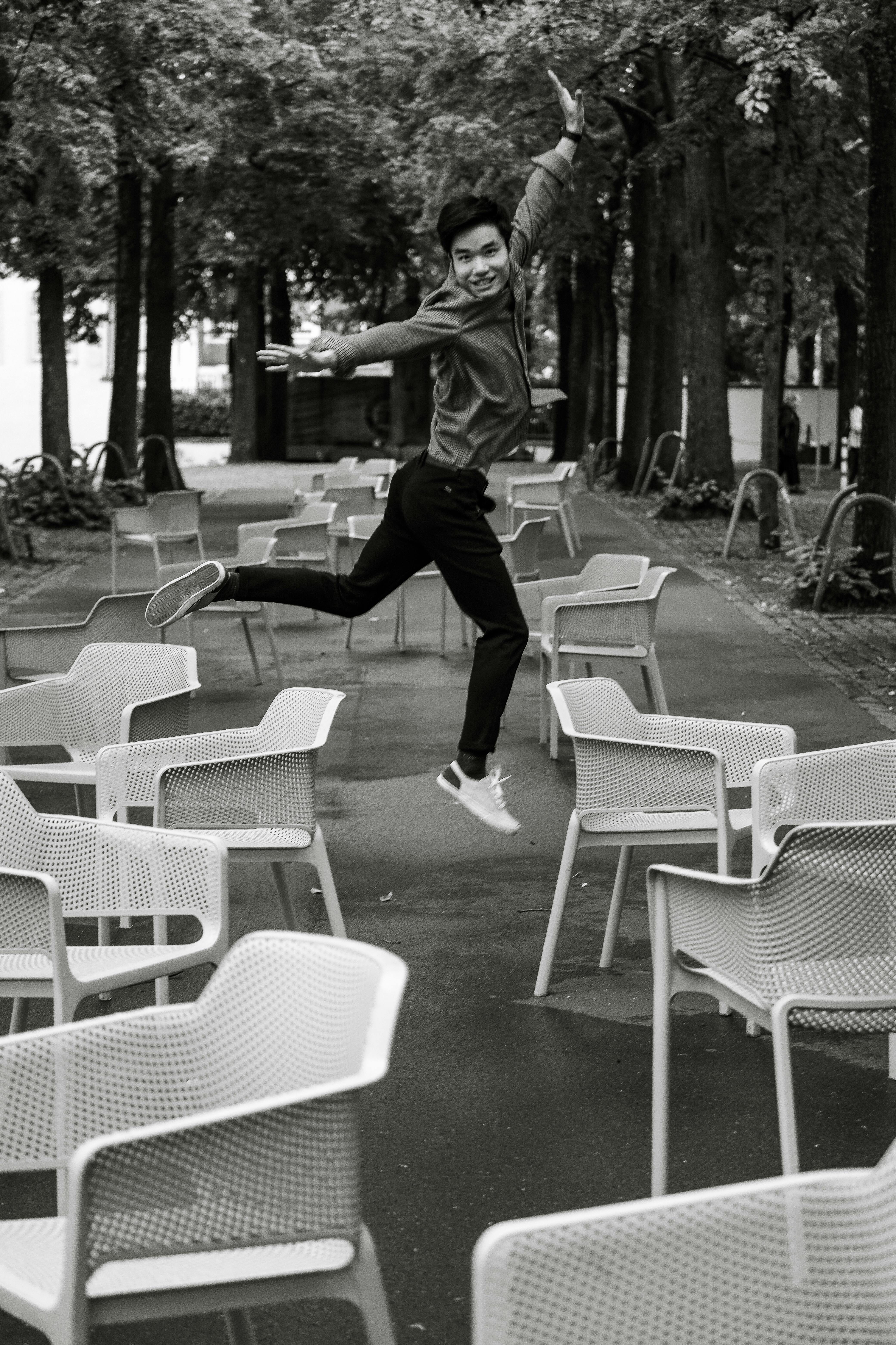 Man in Shirt Jumping among Chairs · Free Stock Photo