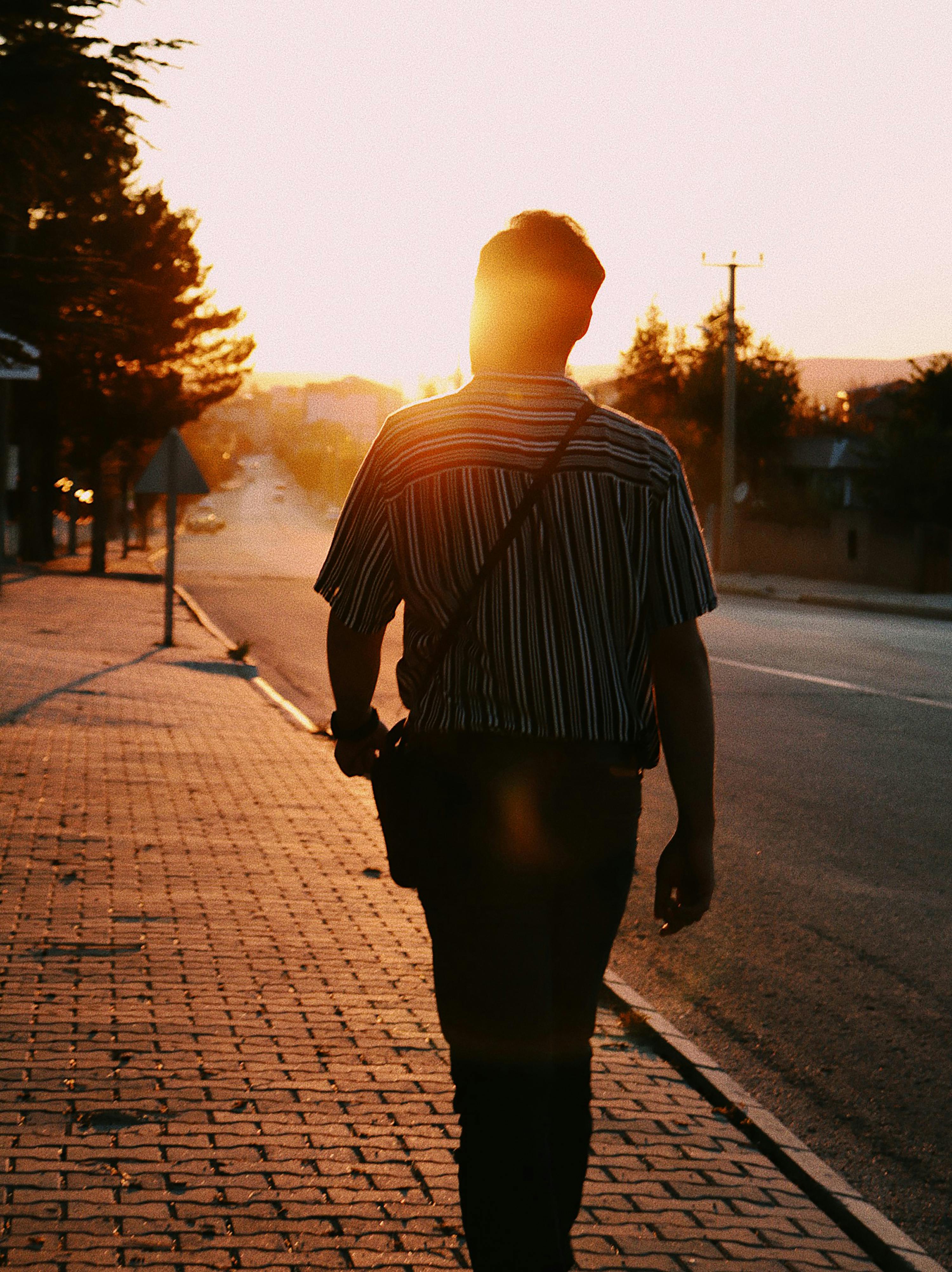 Man Walking on Sidewalk at Sunset · Free Stock Photo