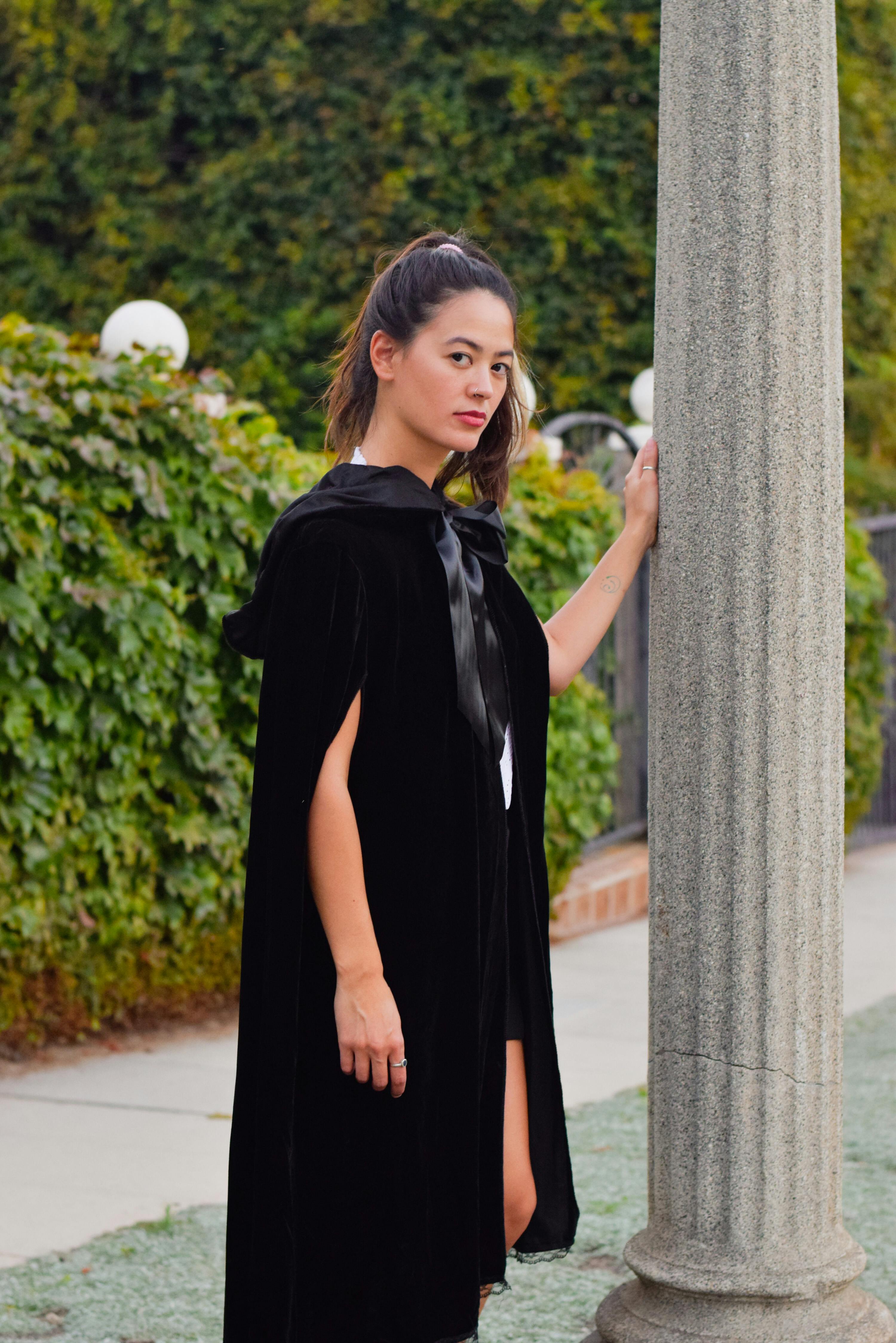 Woman Wearing a Black Cape Standing next to a Column · Free Stock Photo