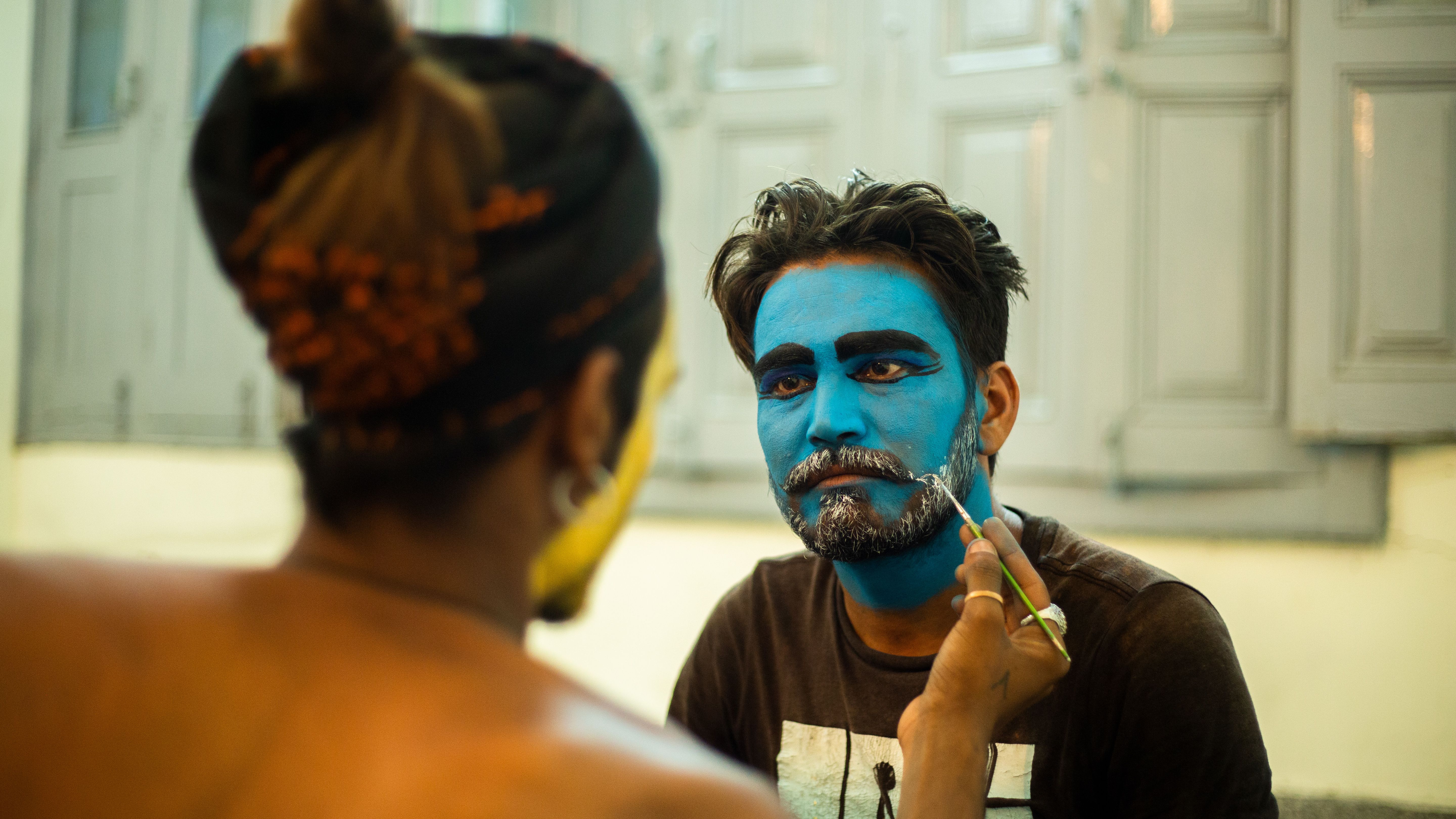 A man with blue face paint is getting his face painted · Free Stock Photo