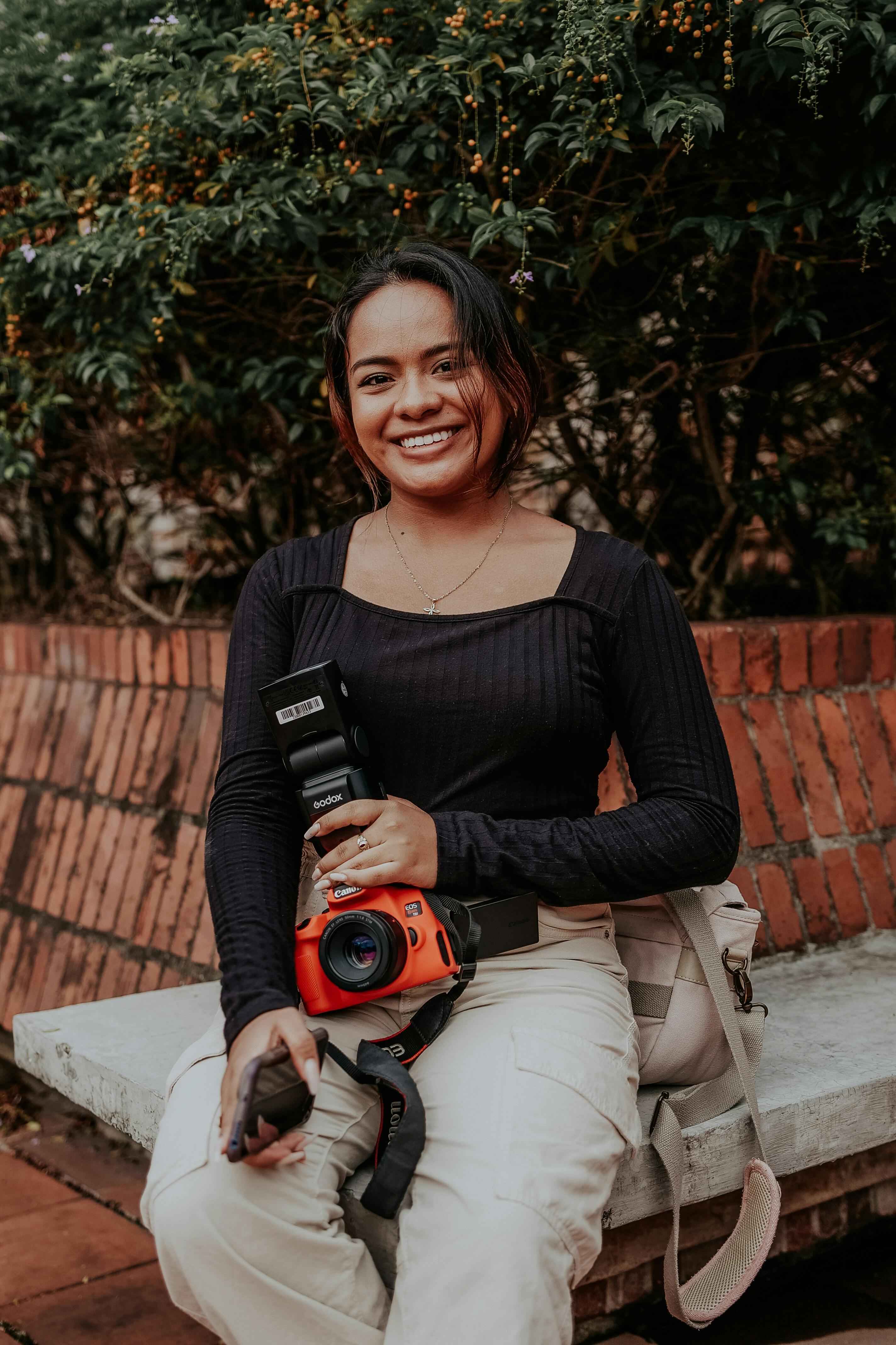 Smiling Woman with Camera Sits on Bench · Free Stock Photo