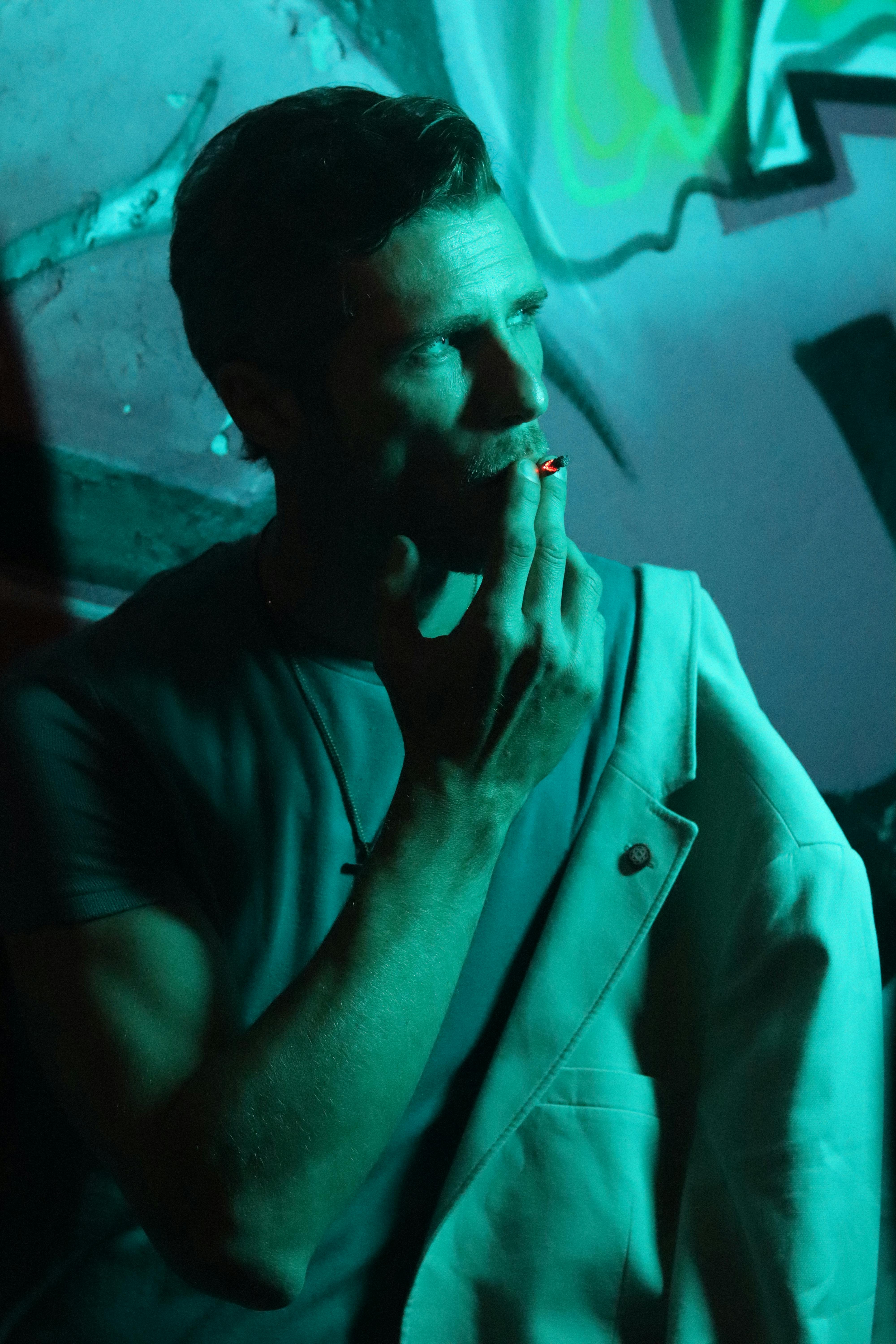 A Man Smoking a Cigarette on the Background of a Wall with Graffiti ...