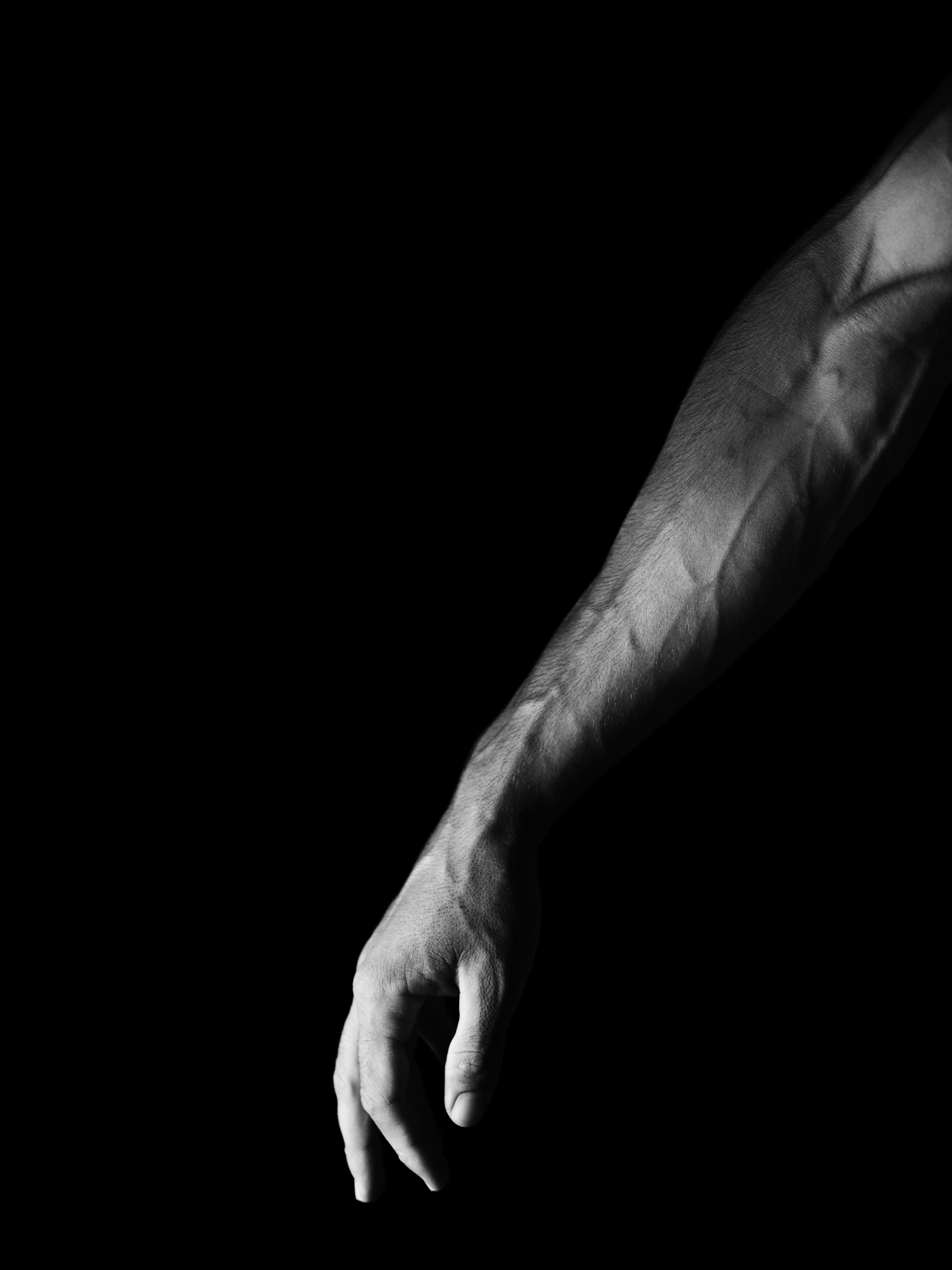Muscular Arm Against Black Background Free Stock Photo