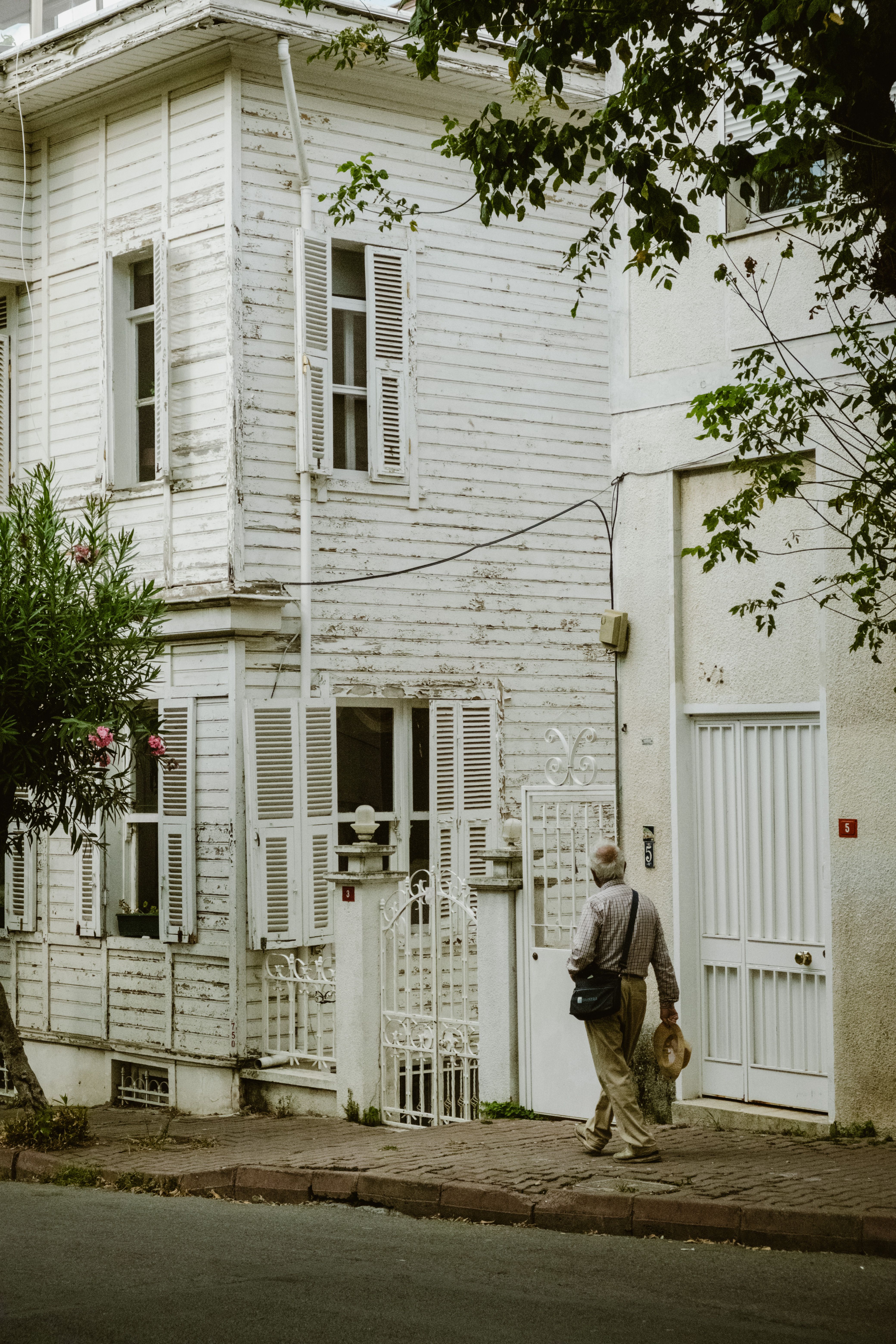 A Man Walking on the Sidewalk in front of a House with Shutters · Free ...