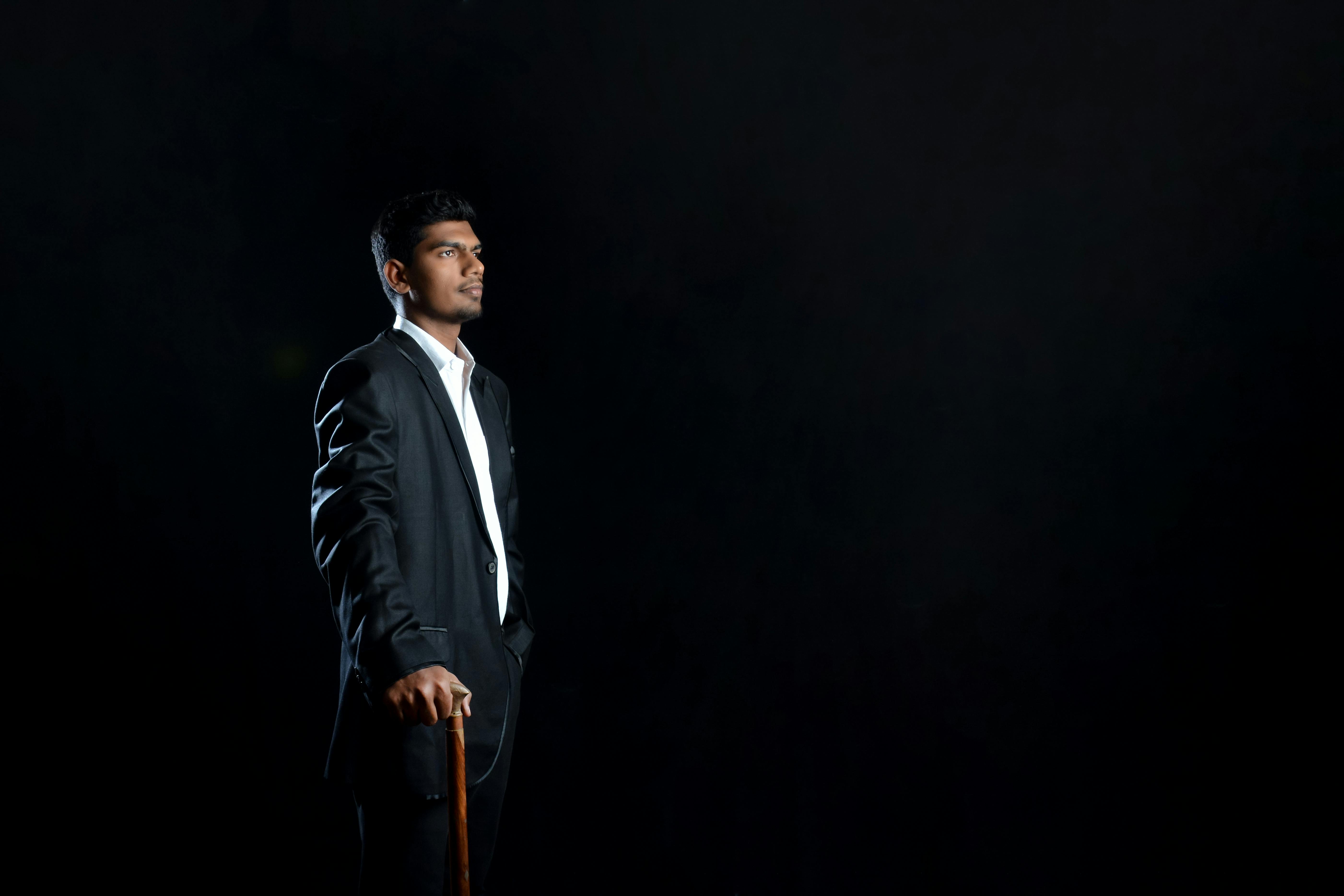 A Man in black formal dress and in hand hold a stick on hand and ...