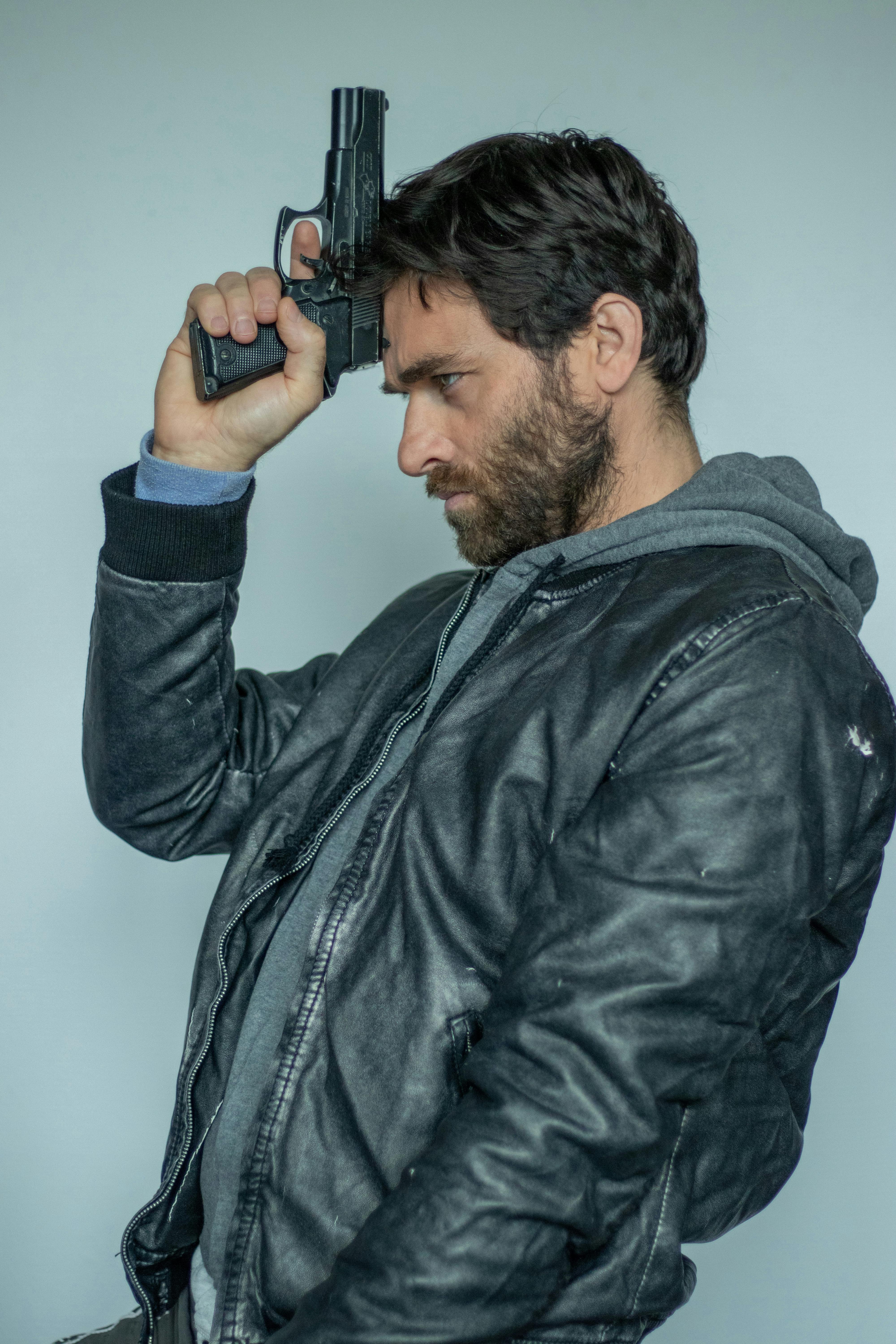 Man in a Leather Jacket Holding a Gun · Free Stock Photo