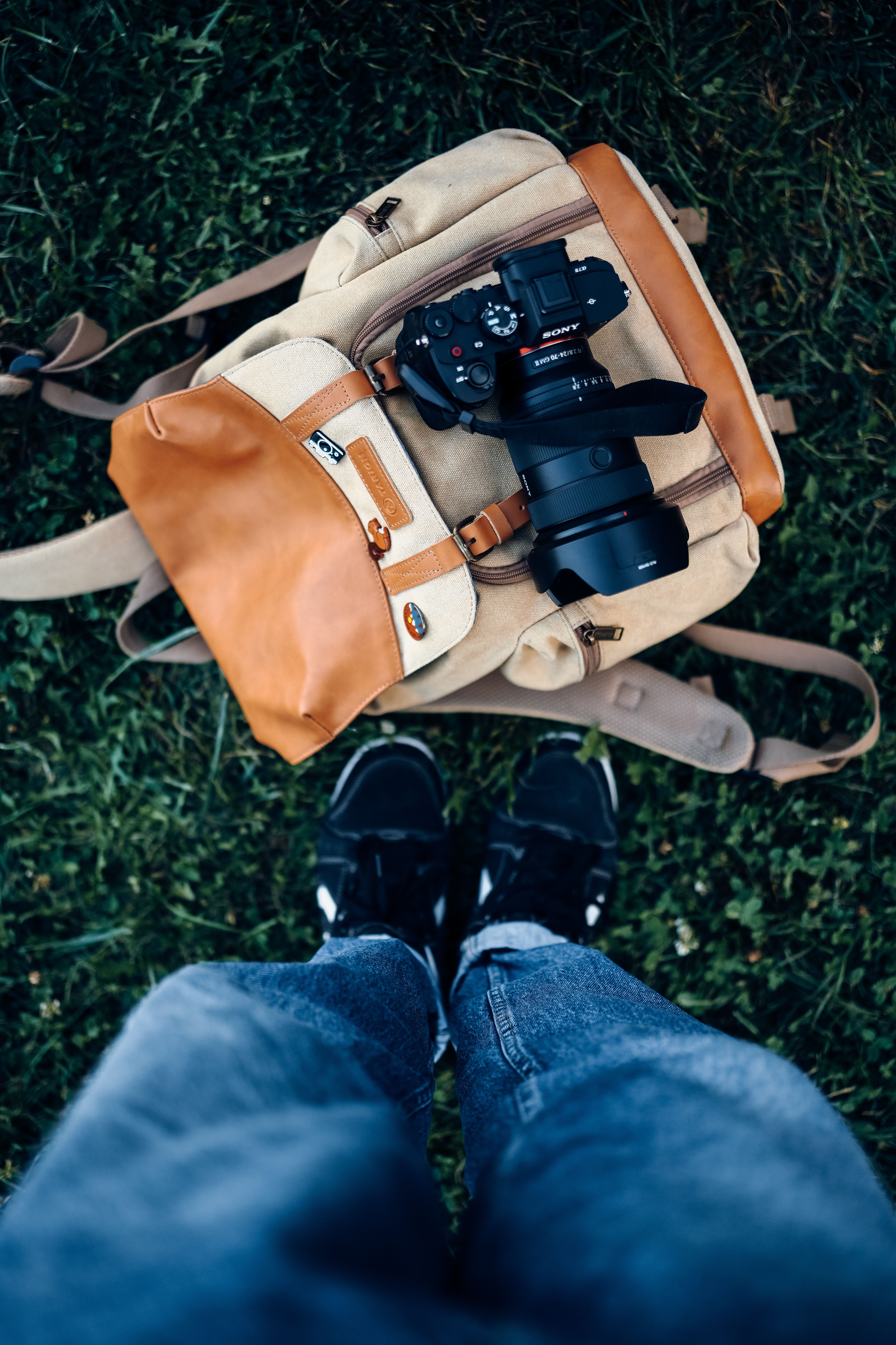 Legs of Person Standing over Backpack with Camera · Free Stock Photo