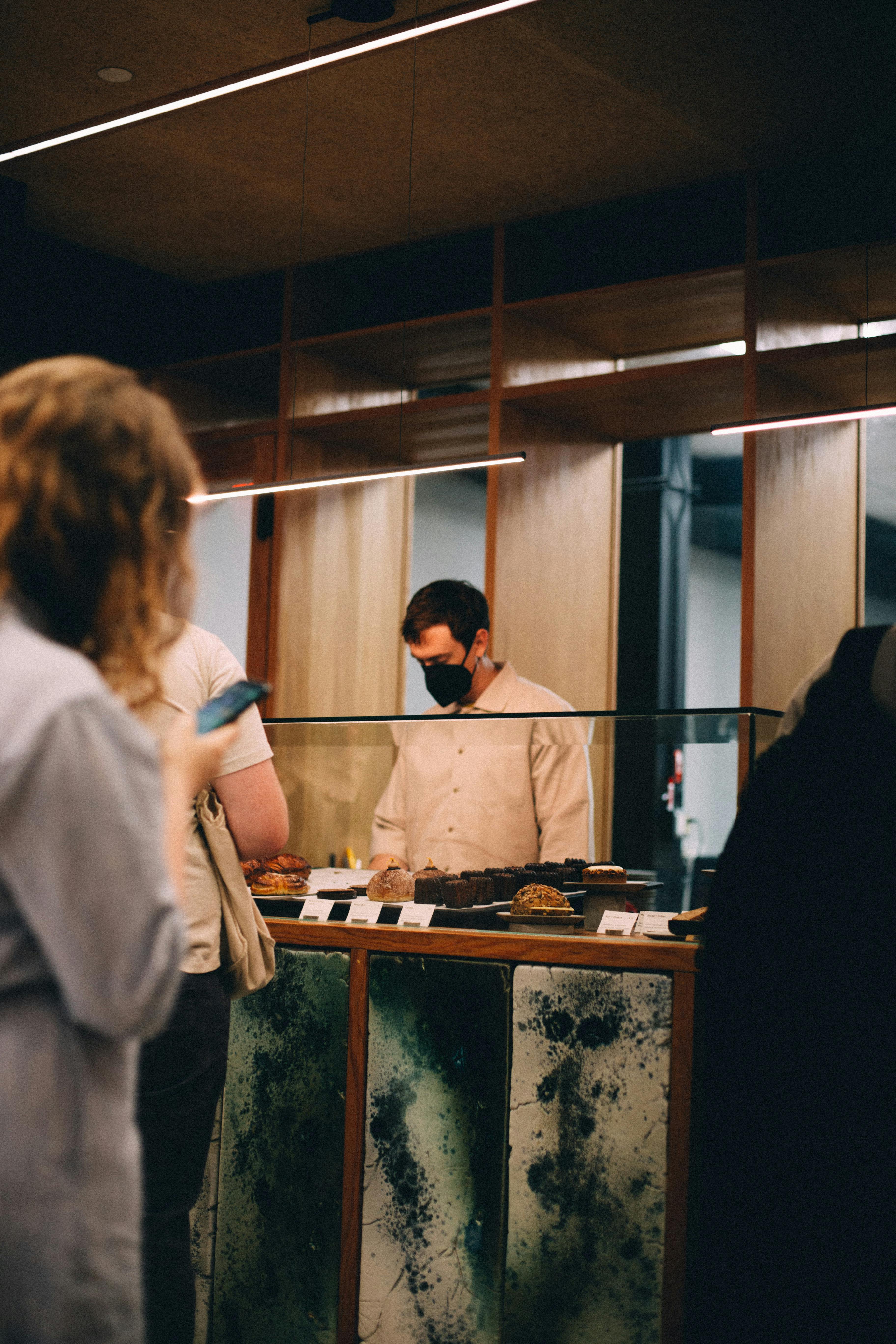 Man in Mask behind Counter at Bakery · Free Stock Photo