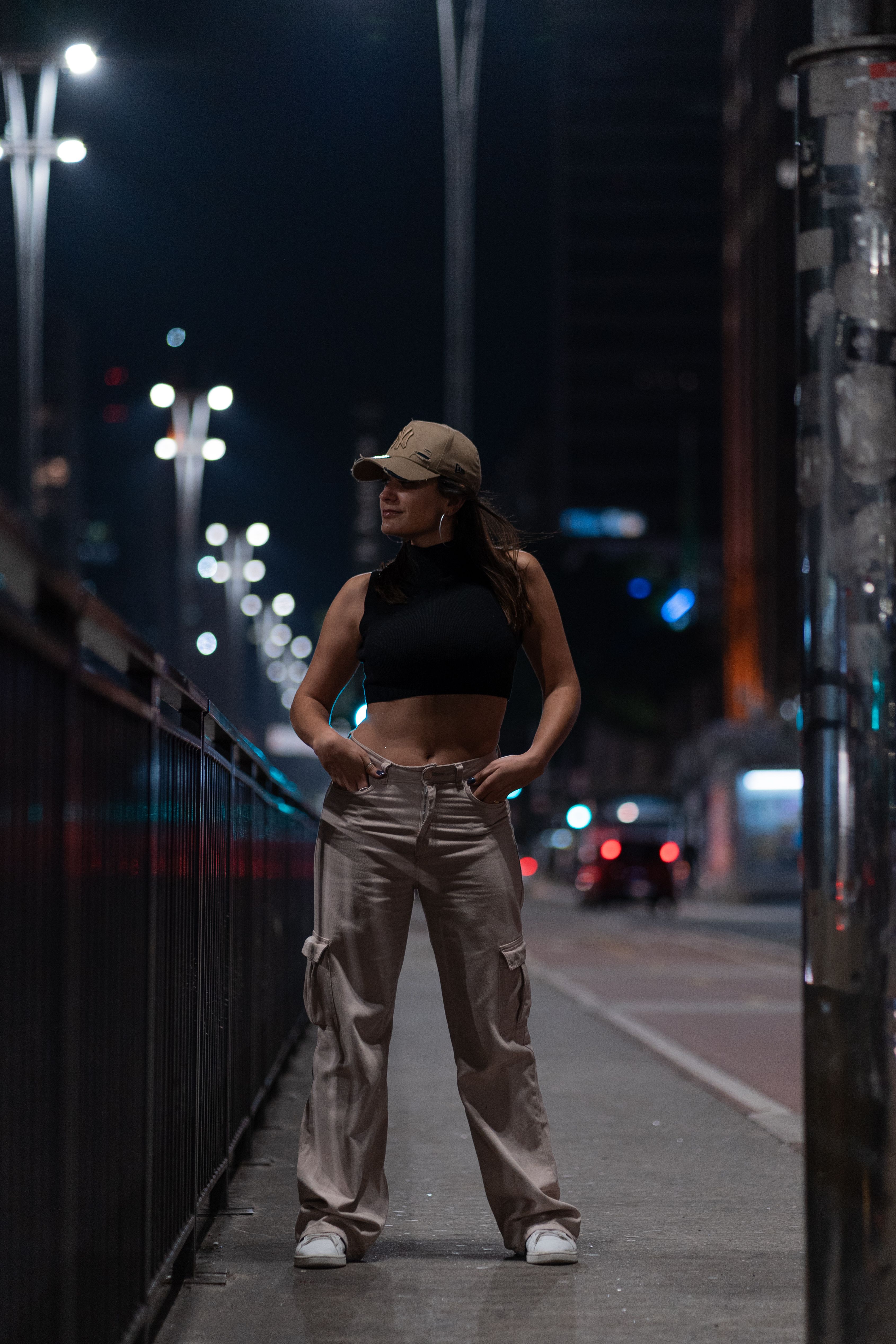 Woman in Turtleneck Top and Baseball Cap Standing on Sidewalk at Night ...