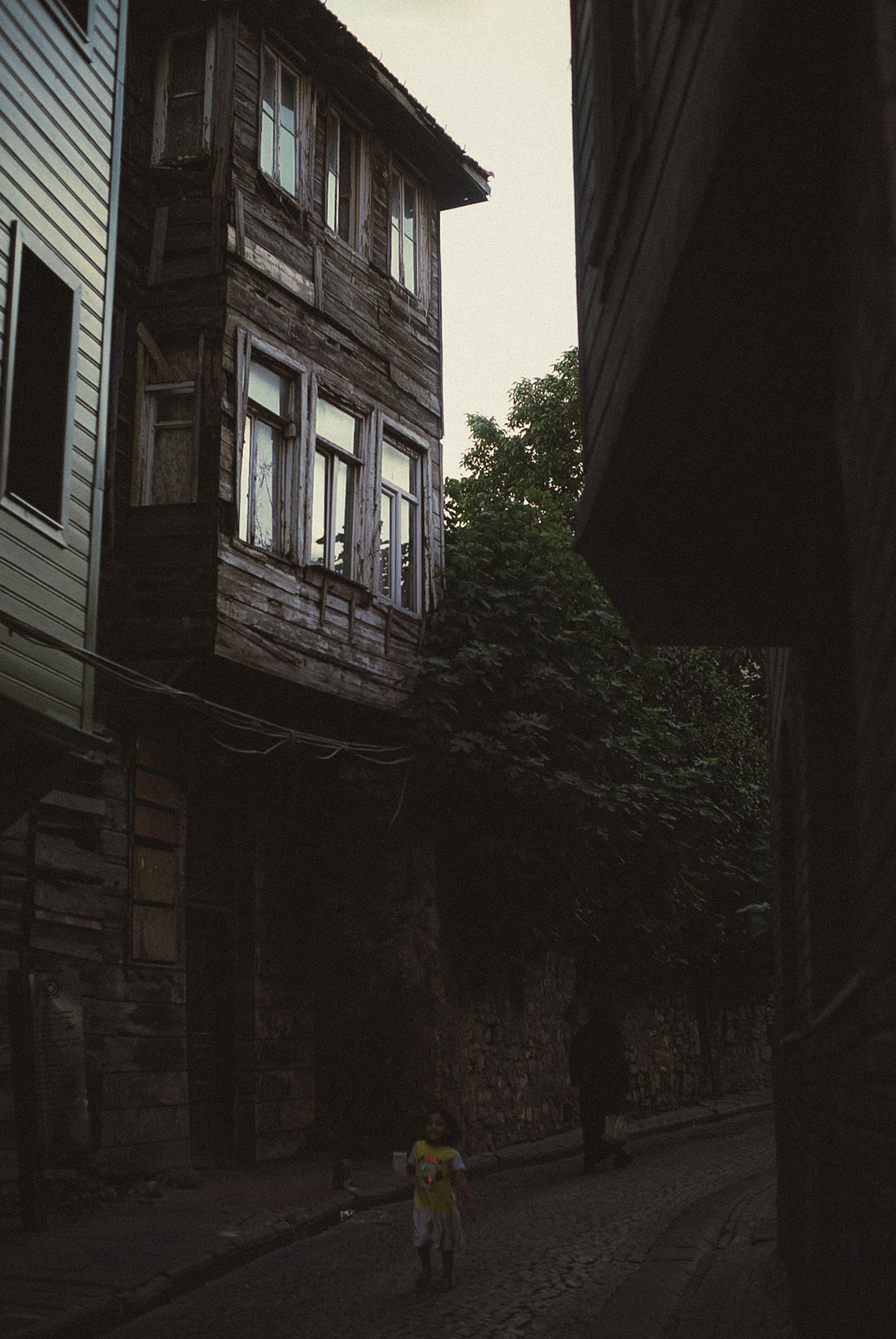 Child Running down Cobblestone Street past Wooden Building · Free Stock ...
