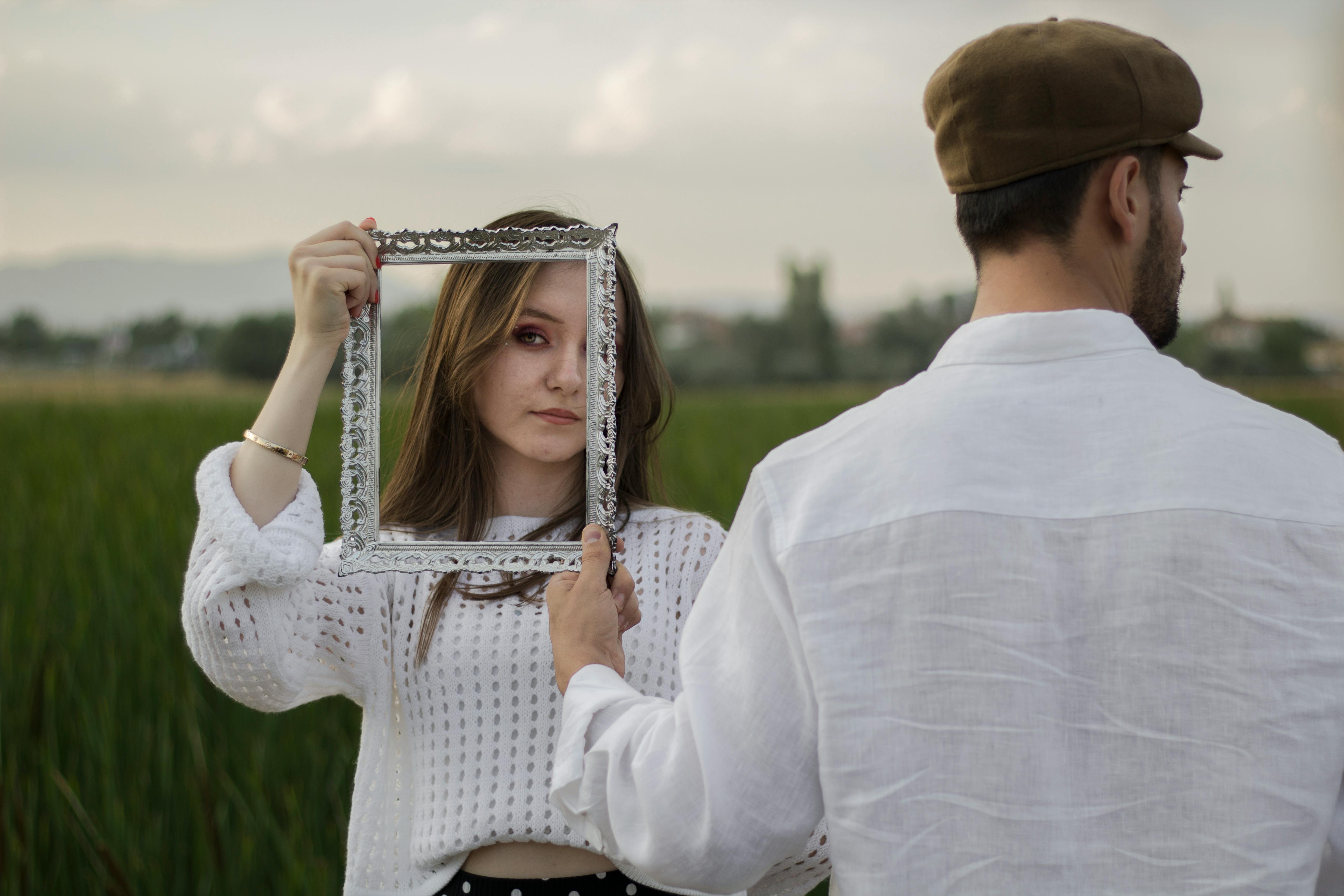 Man and Woman Holding a Frame in front of Her Face · Free Stock Photo