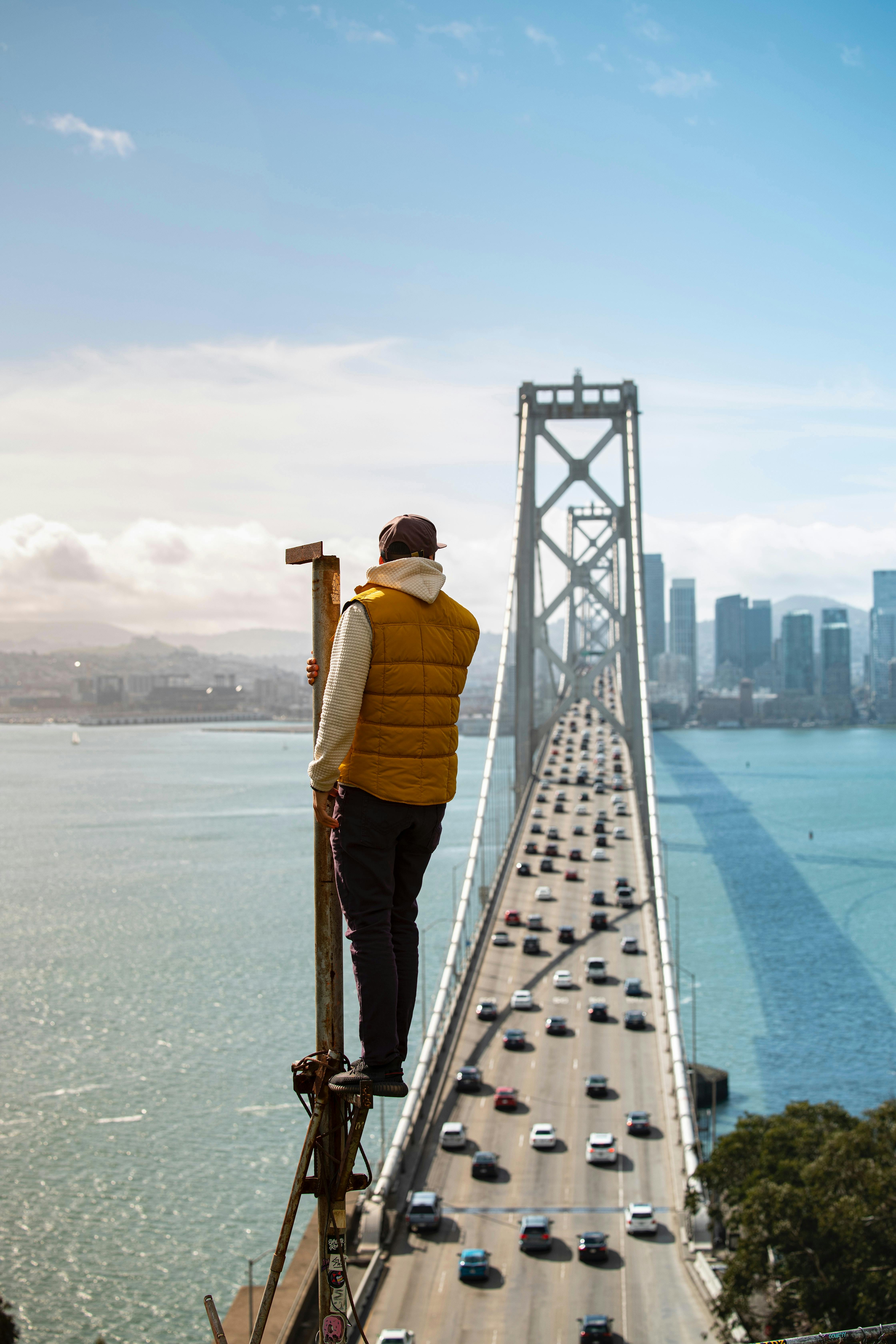Man Standing on a Pole Overlooking a Bridge · Free Stock Photo