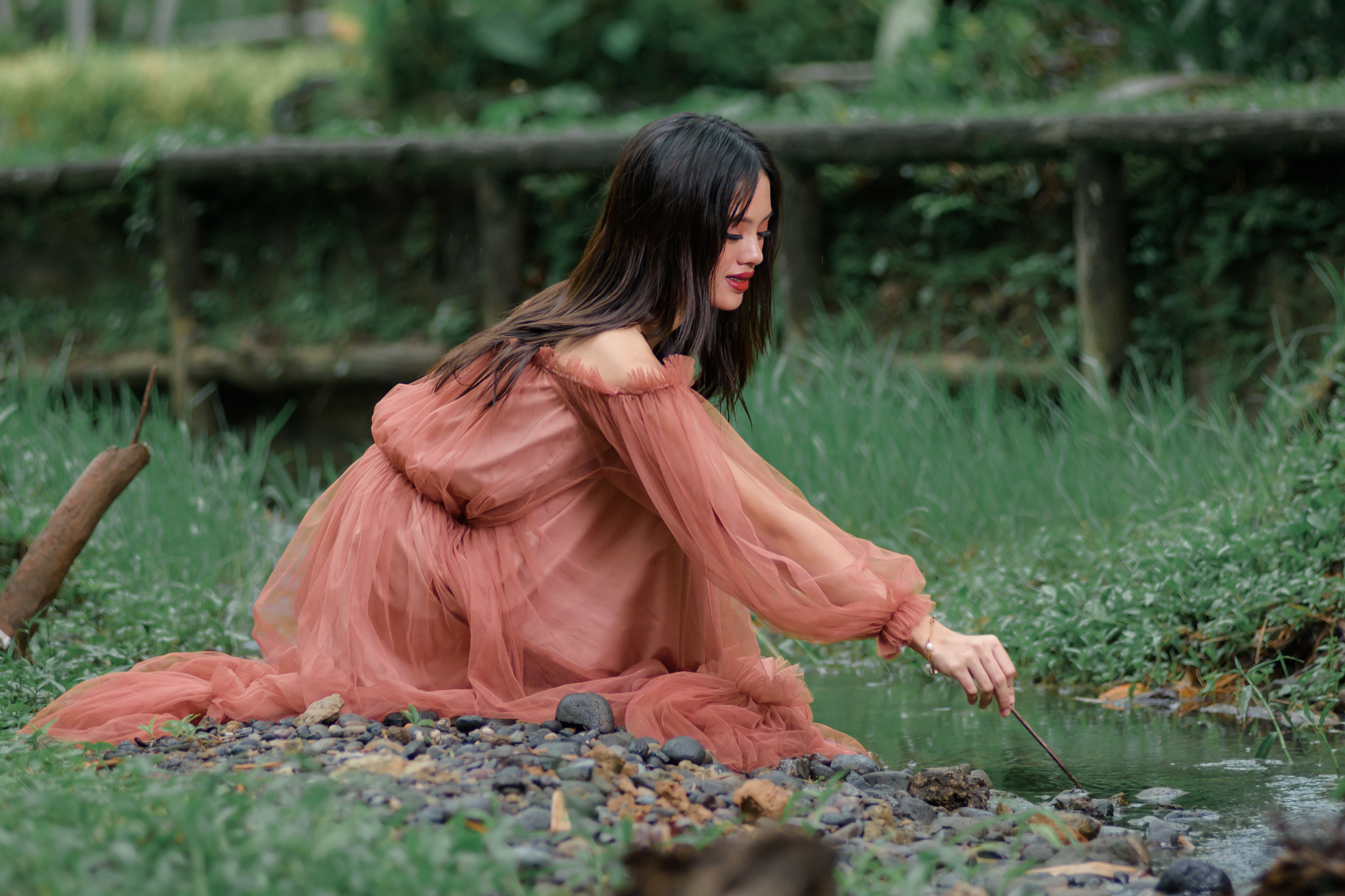 Woman in Dress Squatting by Water · Free Stock Photo
