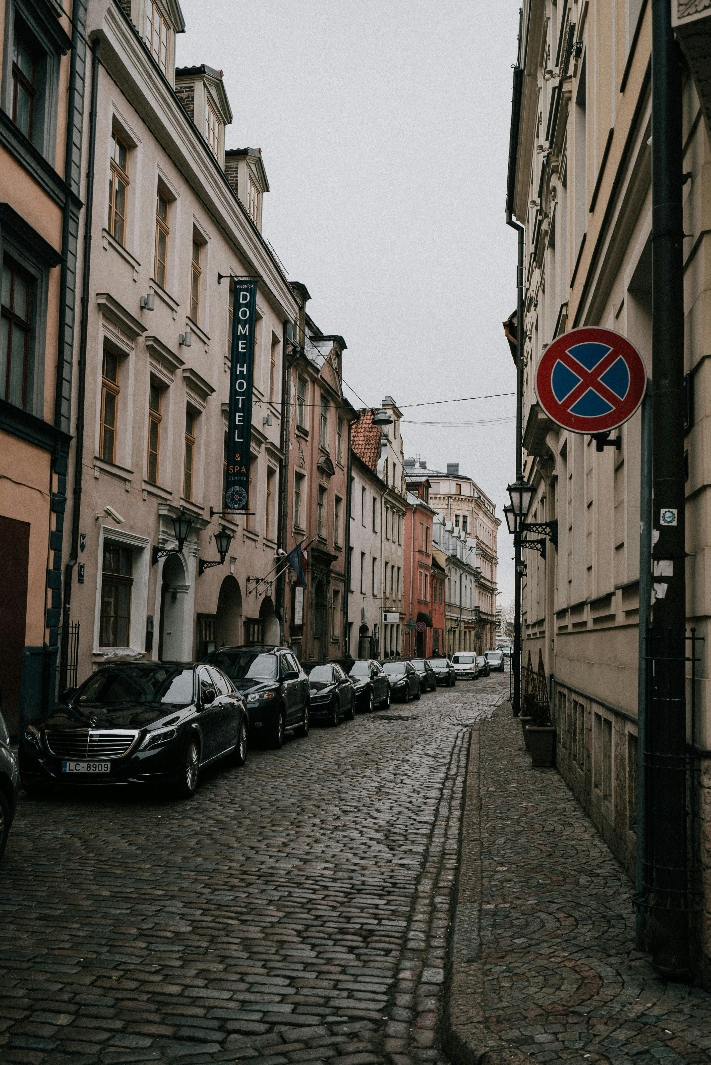 A street with cars parked on it and a sign that says no parking · Free Stock Photo