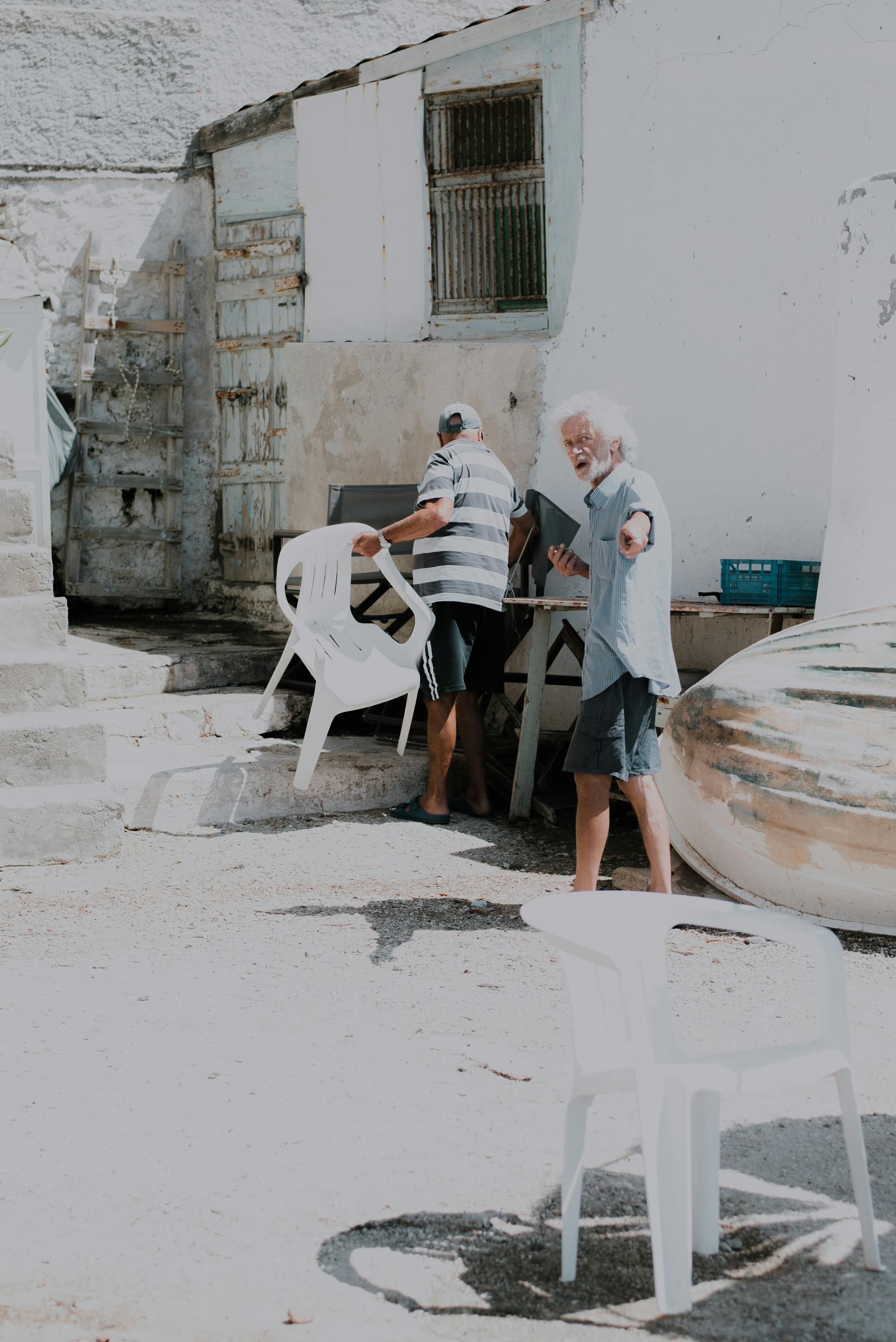 Two Men Carrying Chairs in an Alley · Free Stock Photo