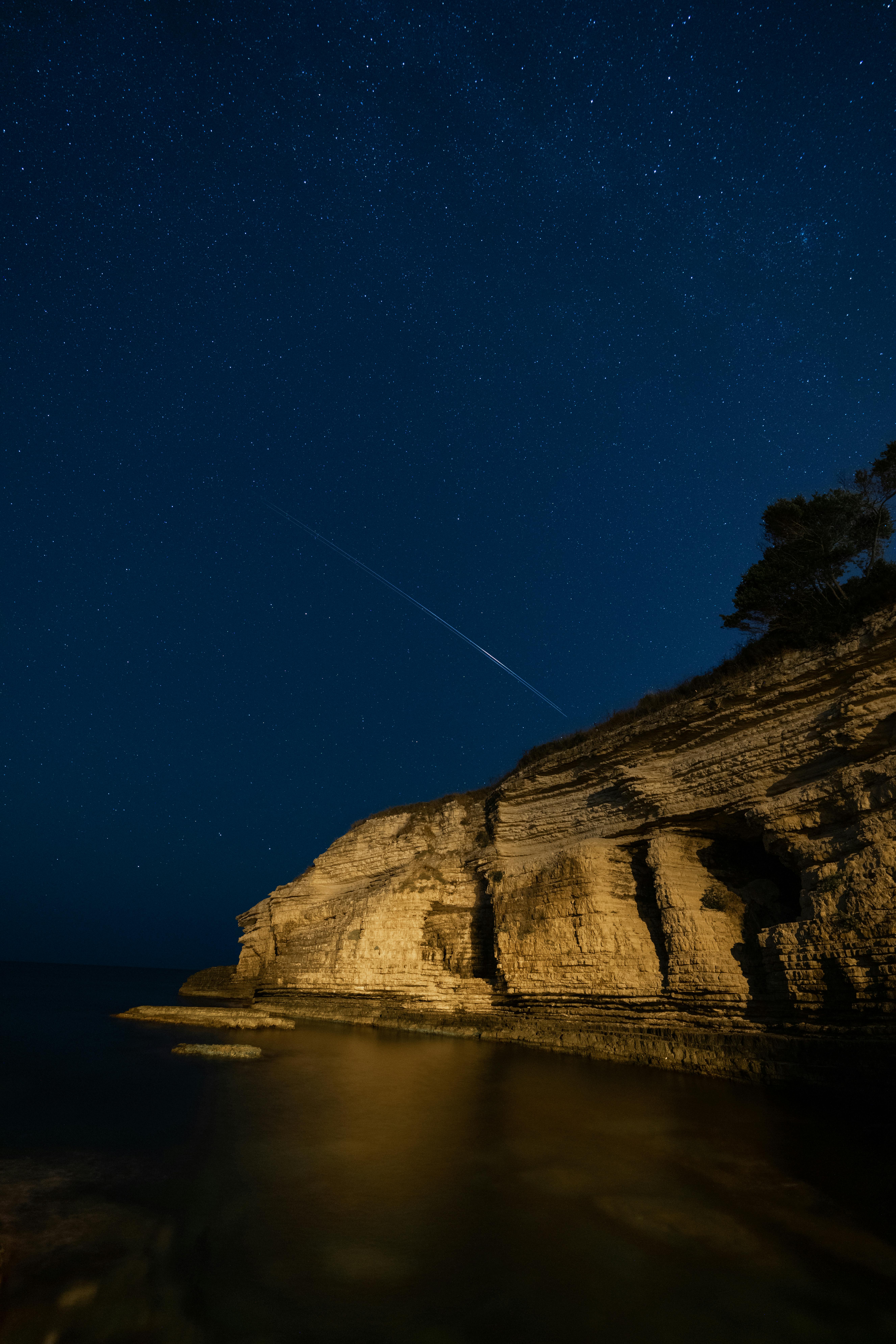 Cliff on the Shore under a Starry Night Sky · Free Stock Photo