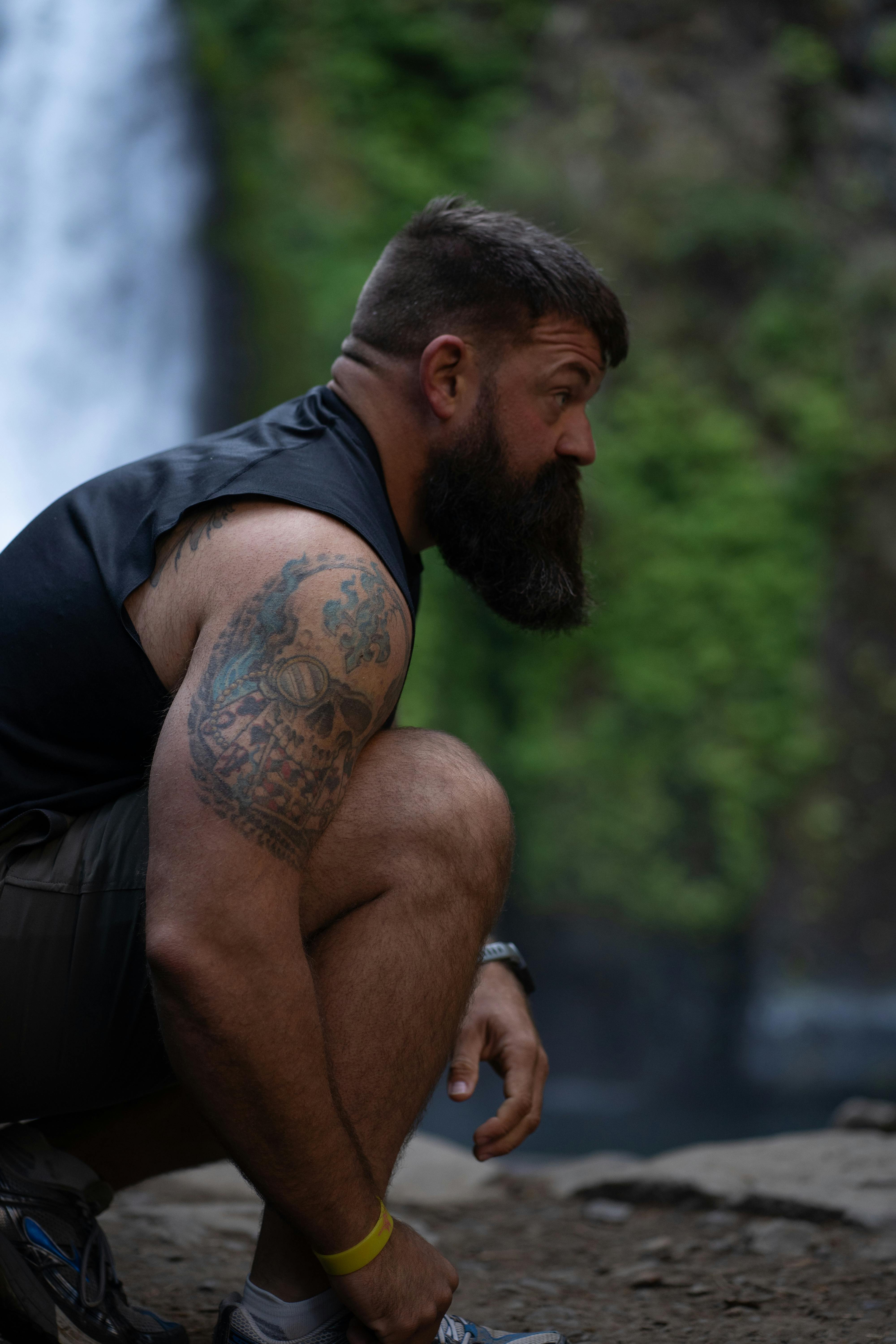 A Bearded Muscular Man Crouching Outside · Free Stock Photo