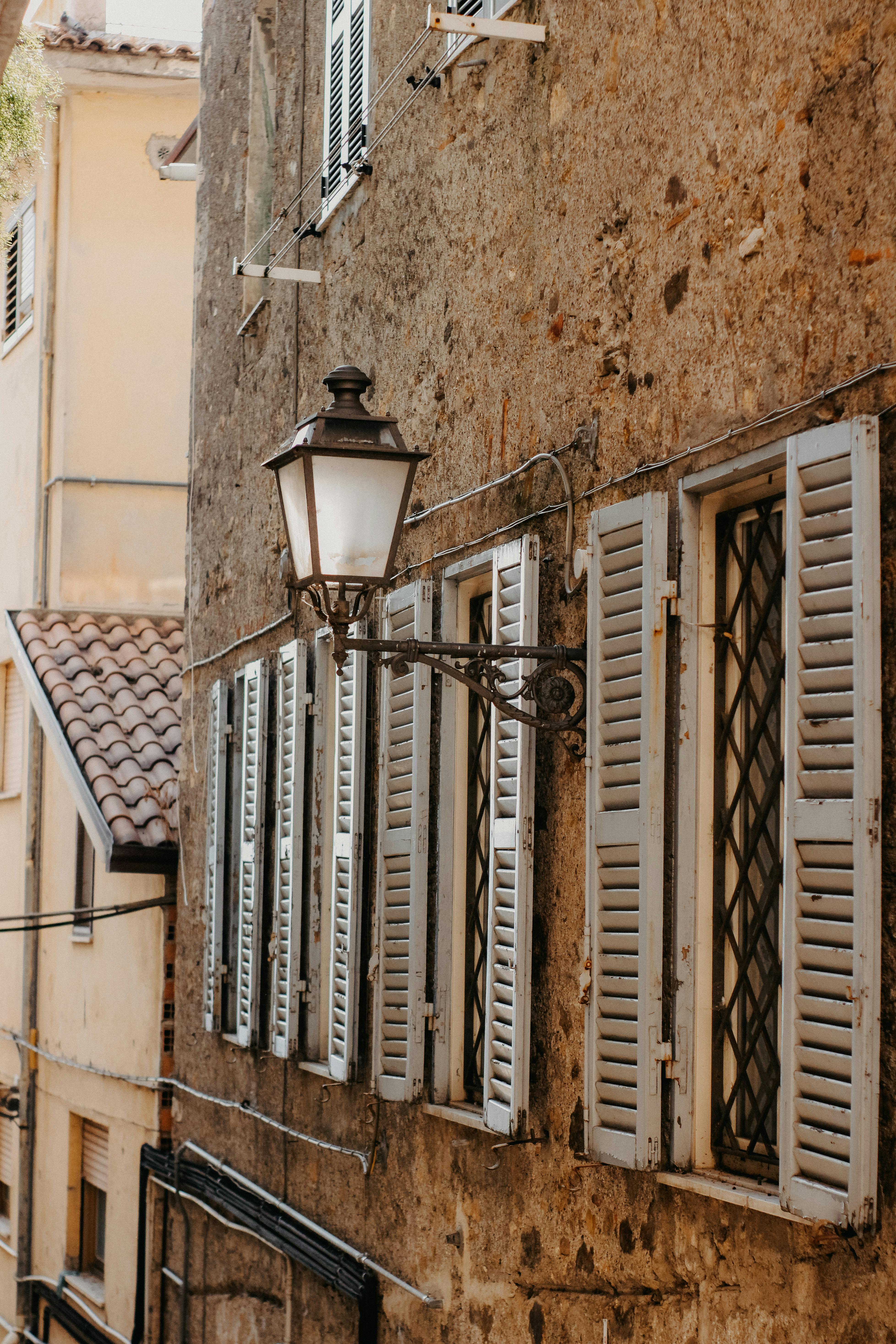 Vintage Street Light on Wall with Shutters on Windows · Free Stock Photo
