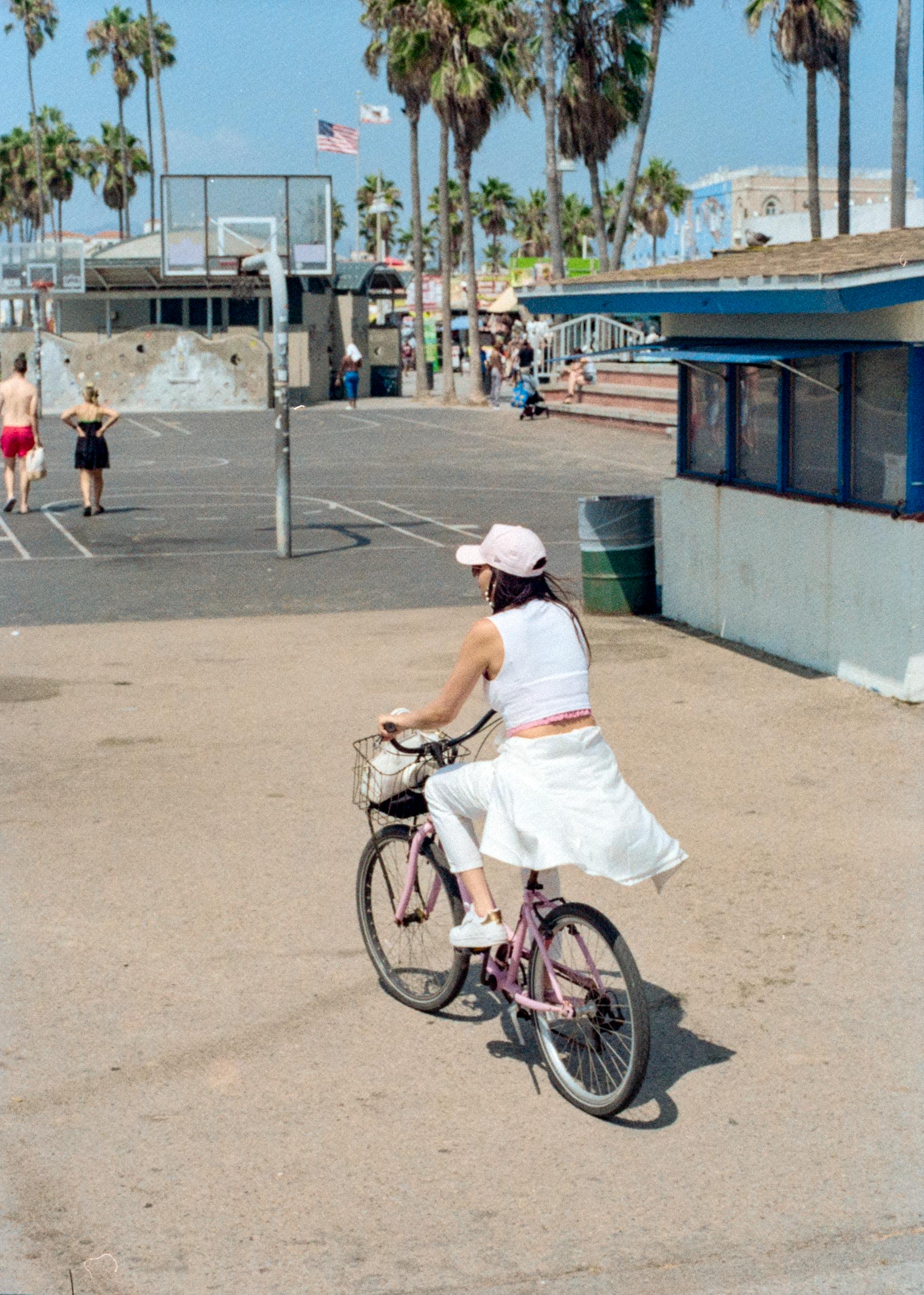 Woman Riding a Bicycle near Outdoor Basketball Court · Free Stock Photo
