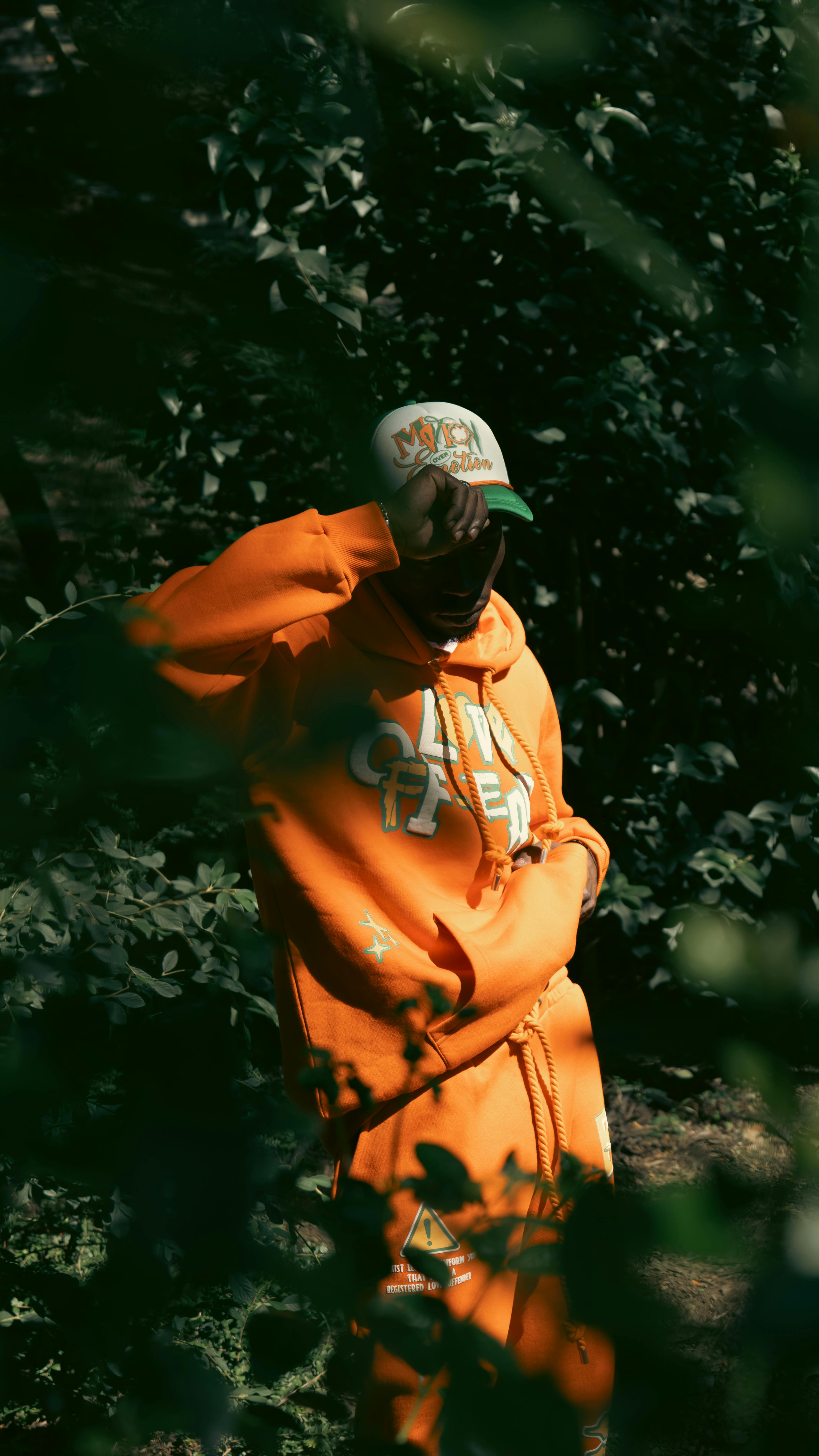 Man Posing in Orange Hooded Sweatshirt and Baseball Cap · Free Stock Photo