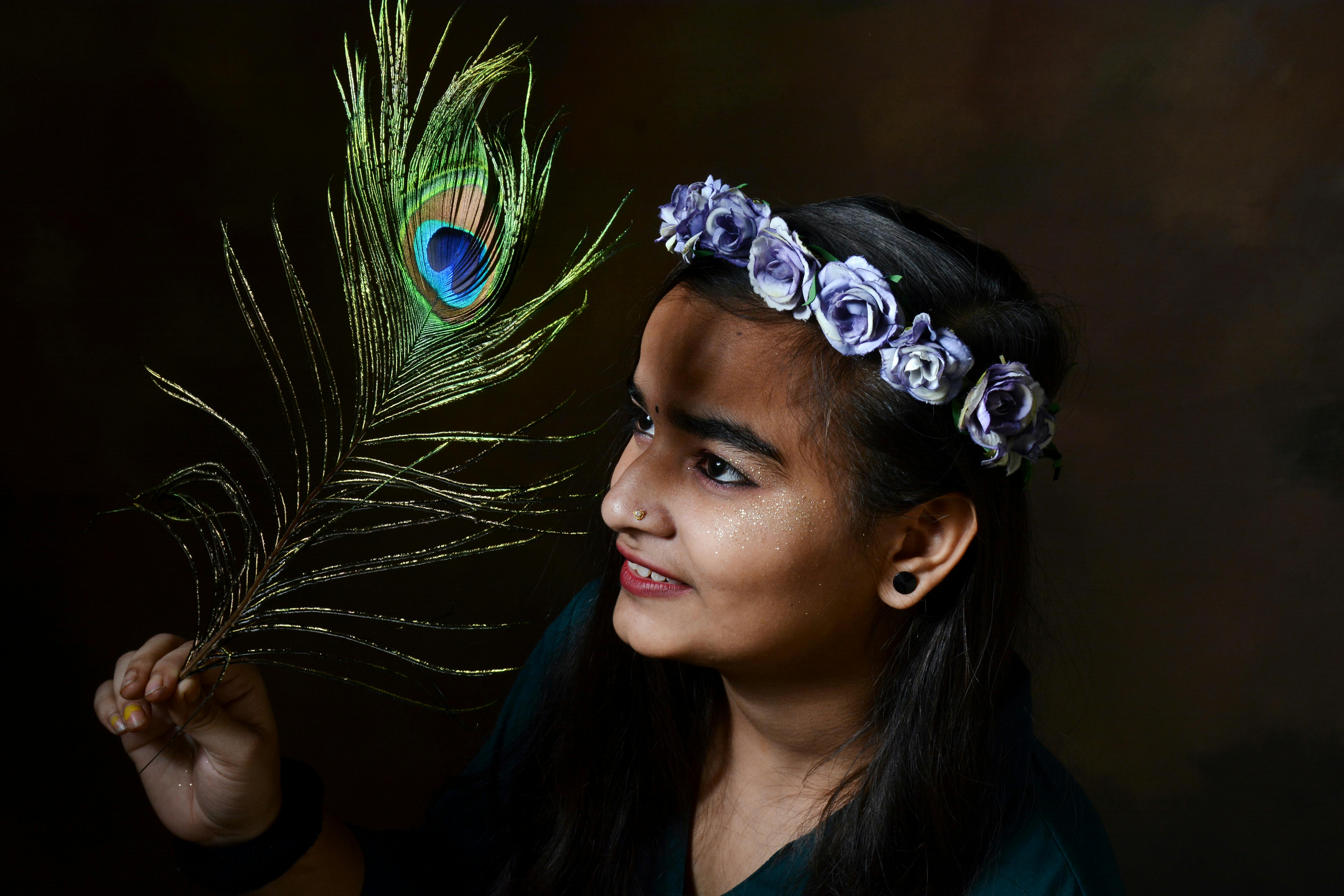 Woman in a Flower Chaplet Holding a Peacock Feather · Free Stock Photo