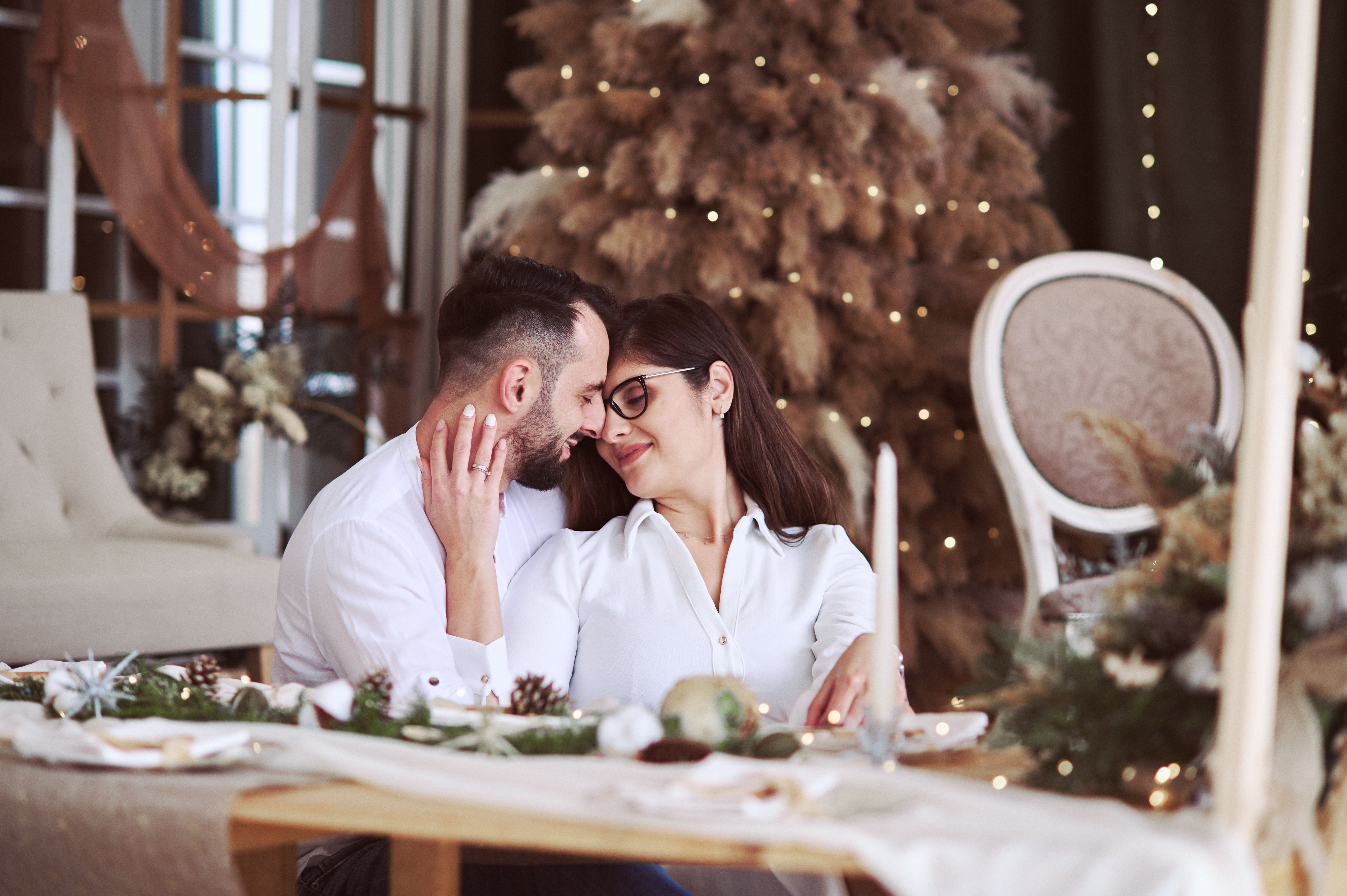 Couple Cuddling at a Christmas Table · Free Stock Photo