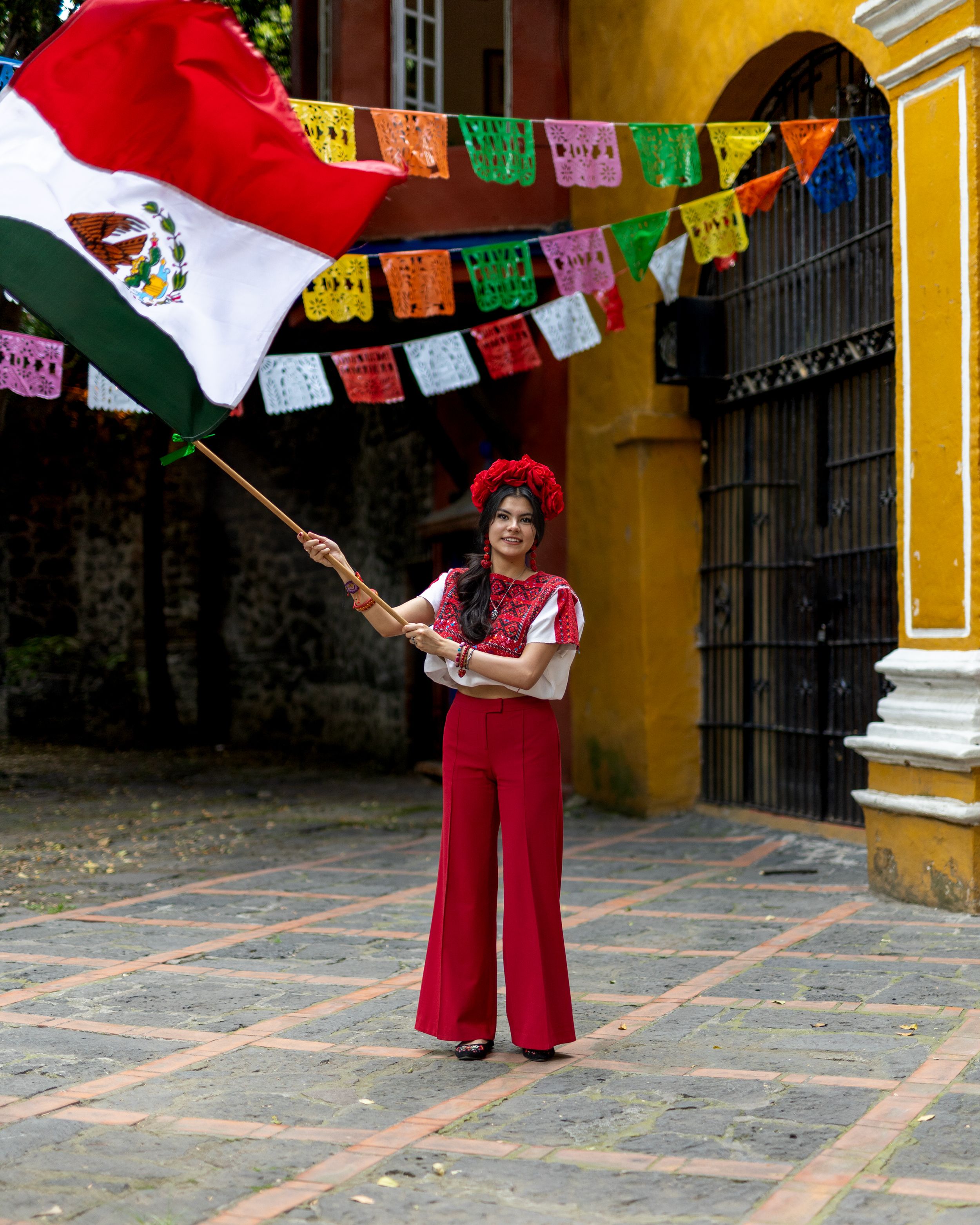 A woman holding a mexican flag in front of a building · Free Stock Photo