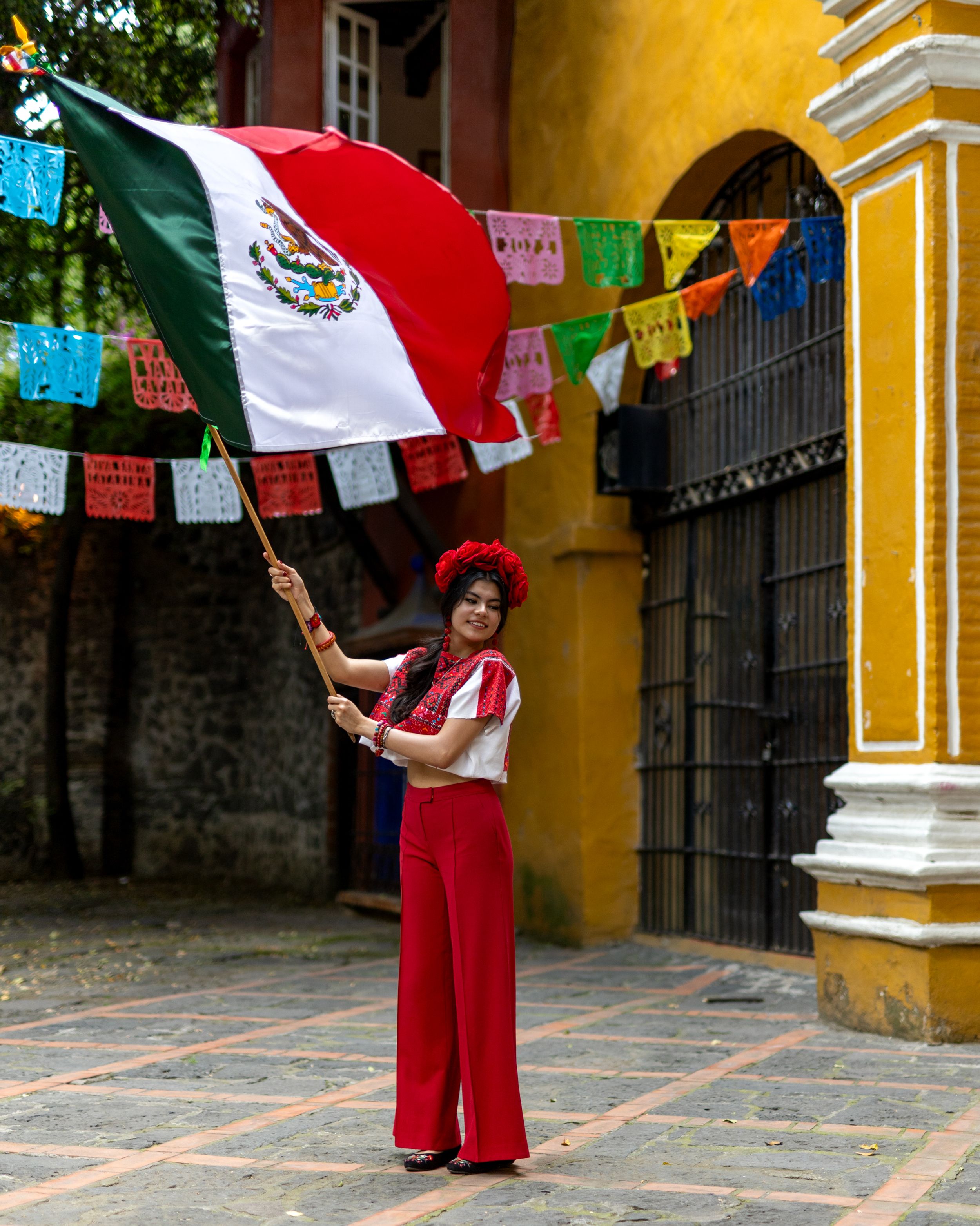 A woman holding a mexican flag in front of a building · Free Stock Photo