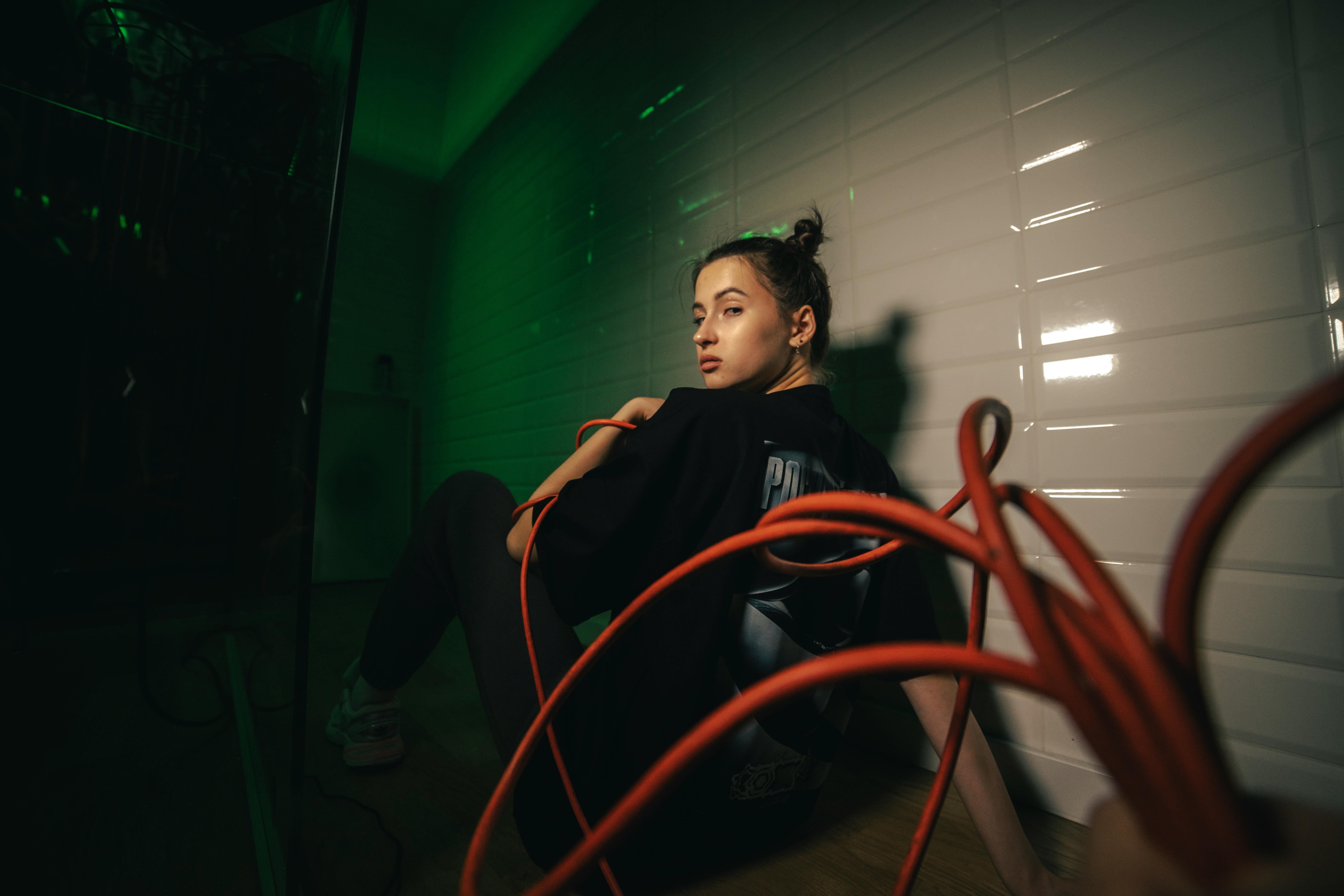 Woman Sitting with Cable near Wall · Free Stock Photo