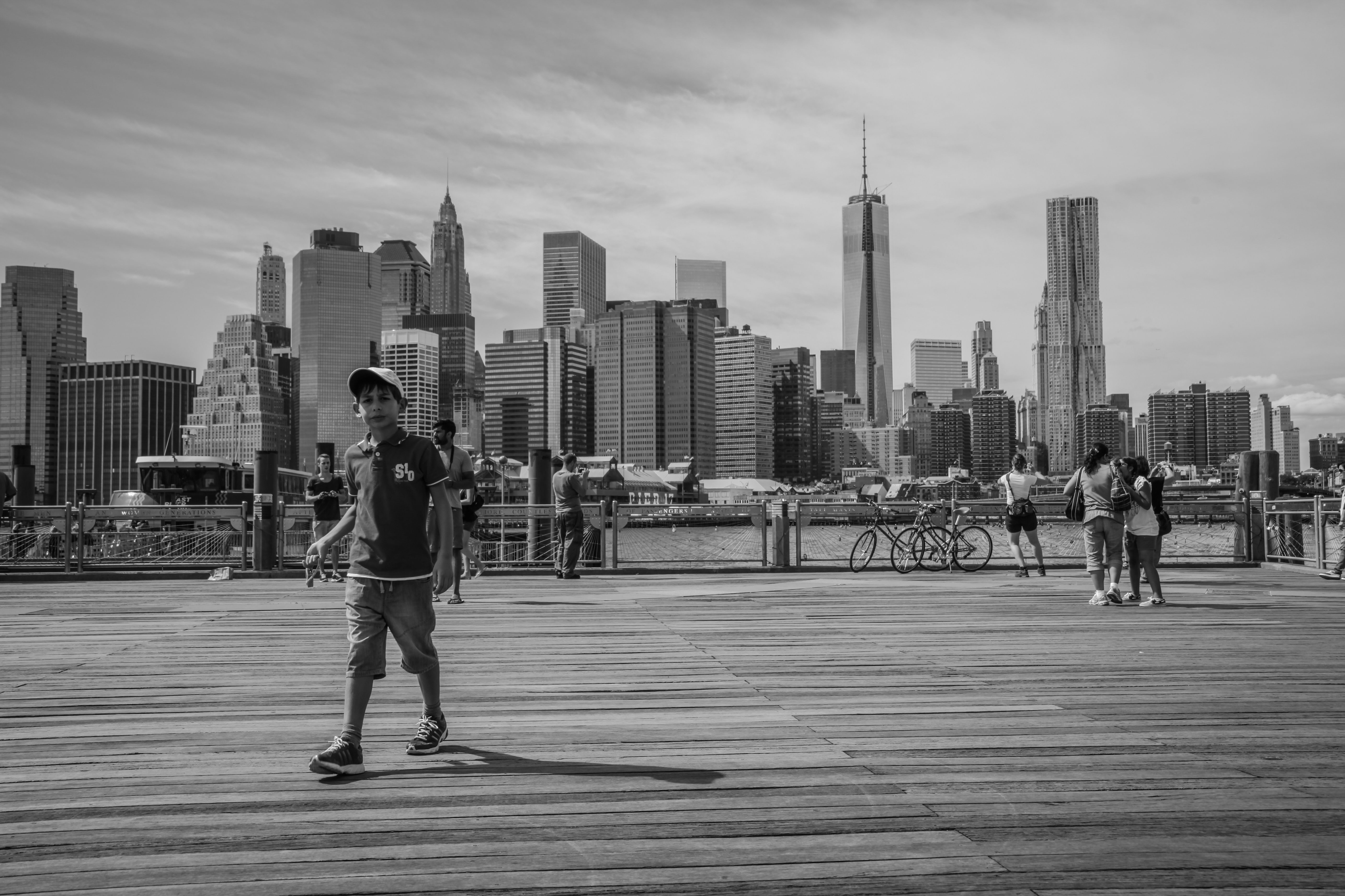 A man walking on the boardwalk in front of a city · Free Stock Photo
