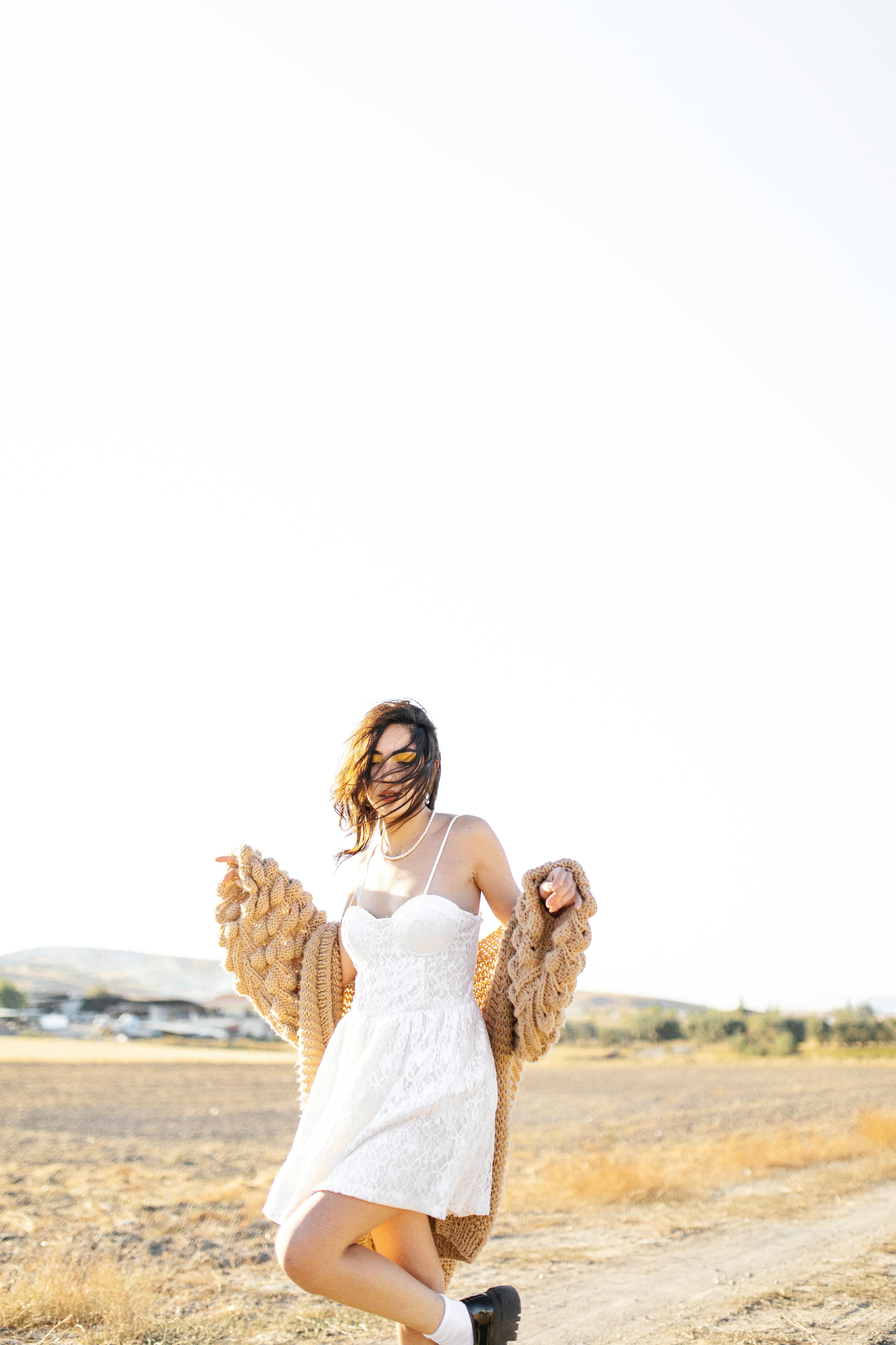 Model in a White Lace Sundress and a Long Beige Cardigan Dancing in a ...