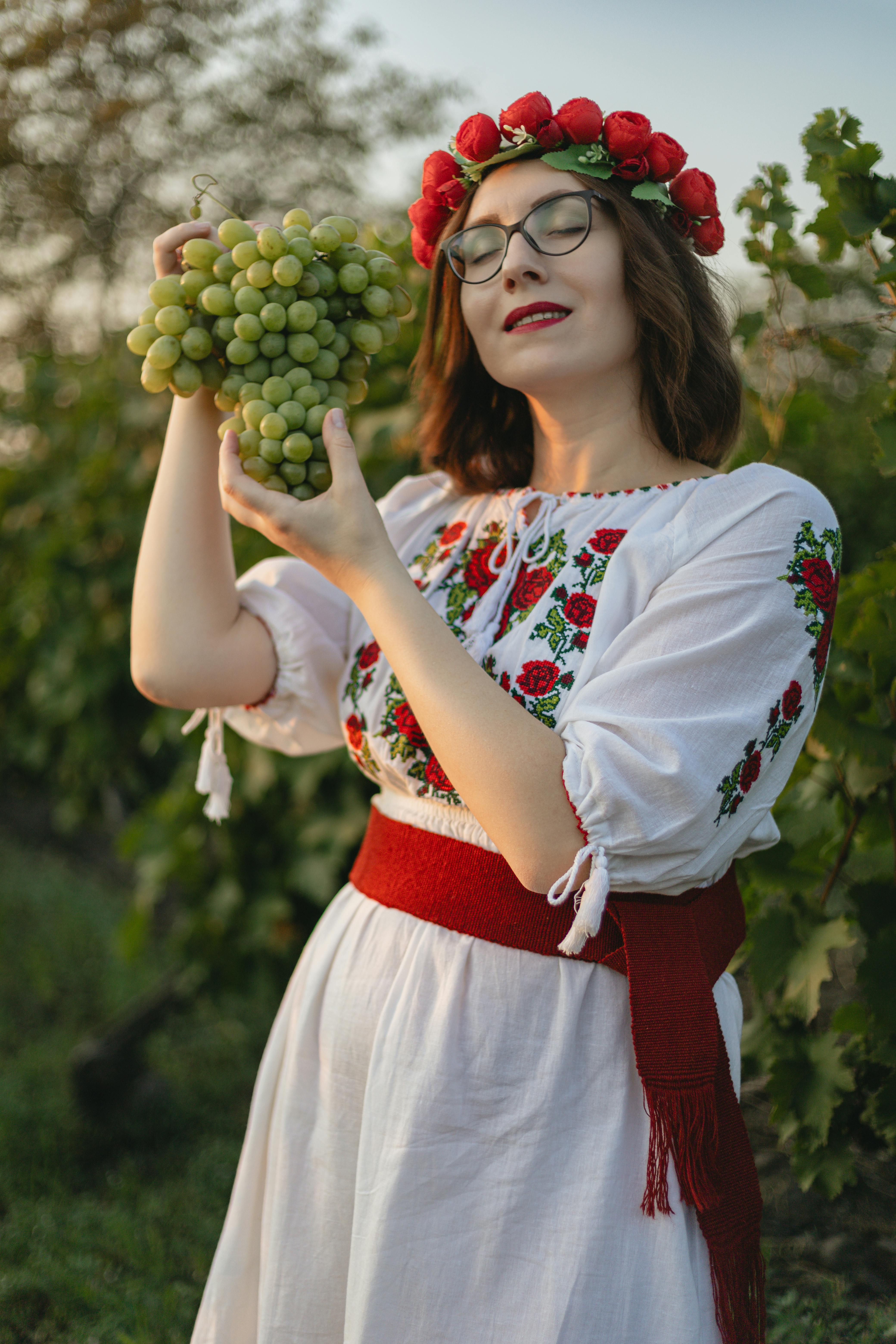 Woman in Traditional Clothing Holding Grapes · Free Stock Photo