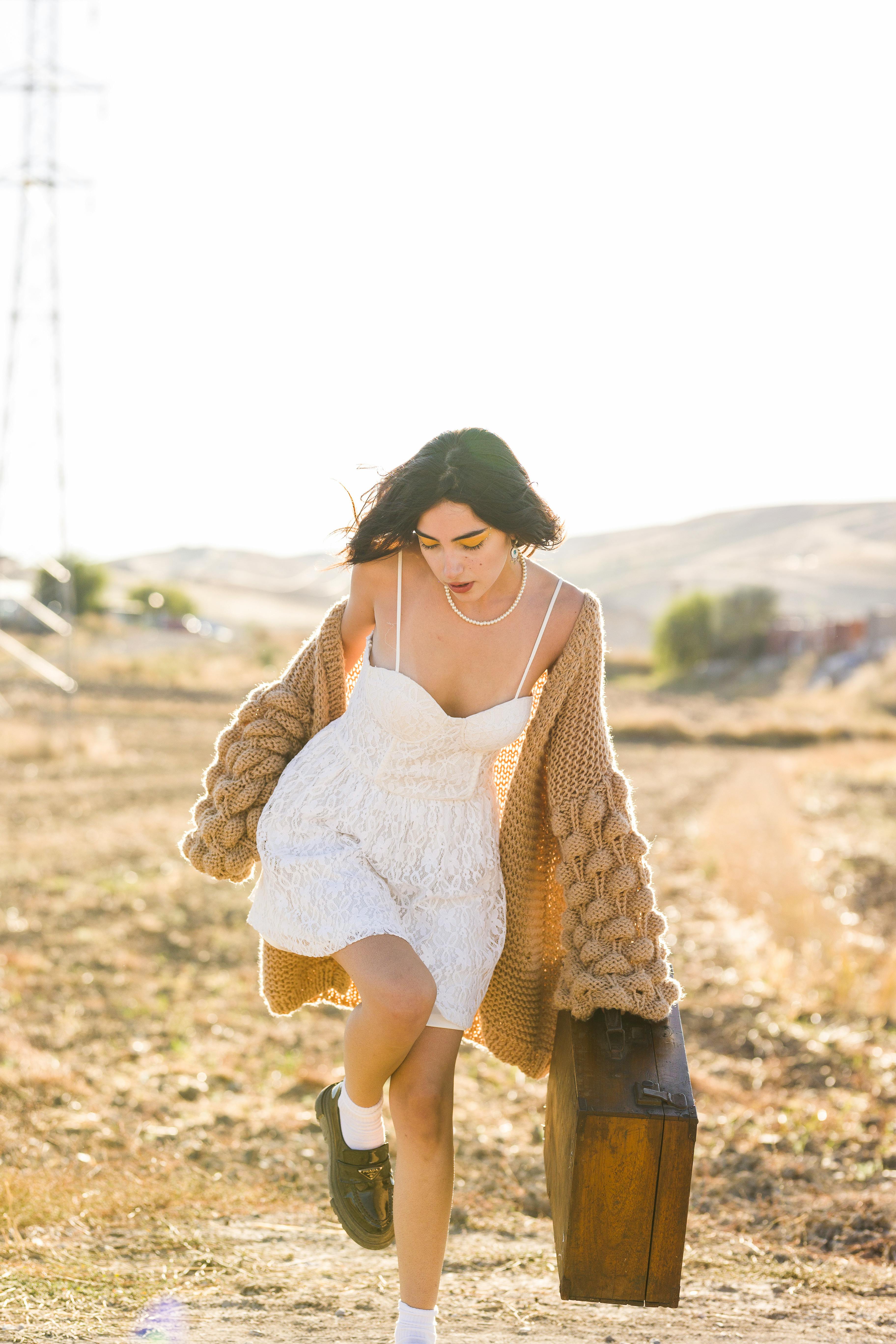 Woman Wearing White Sundress and Sweater Walking with Wooden Suitcase ...