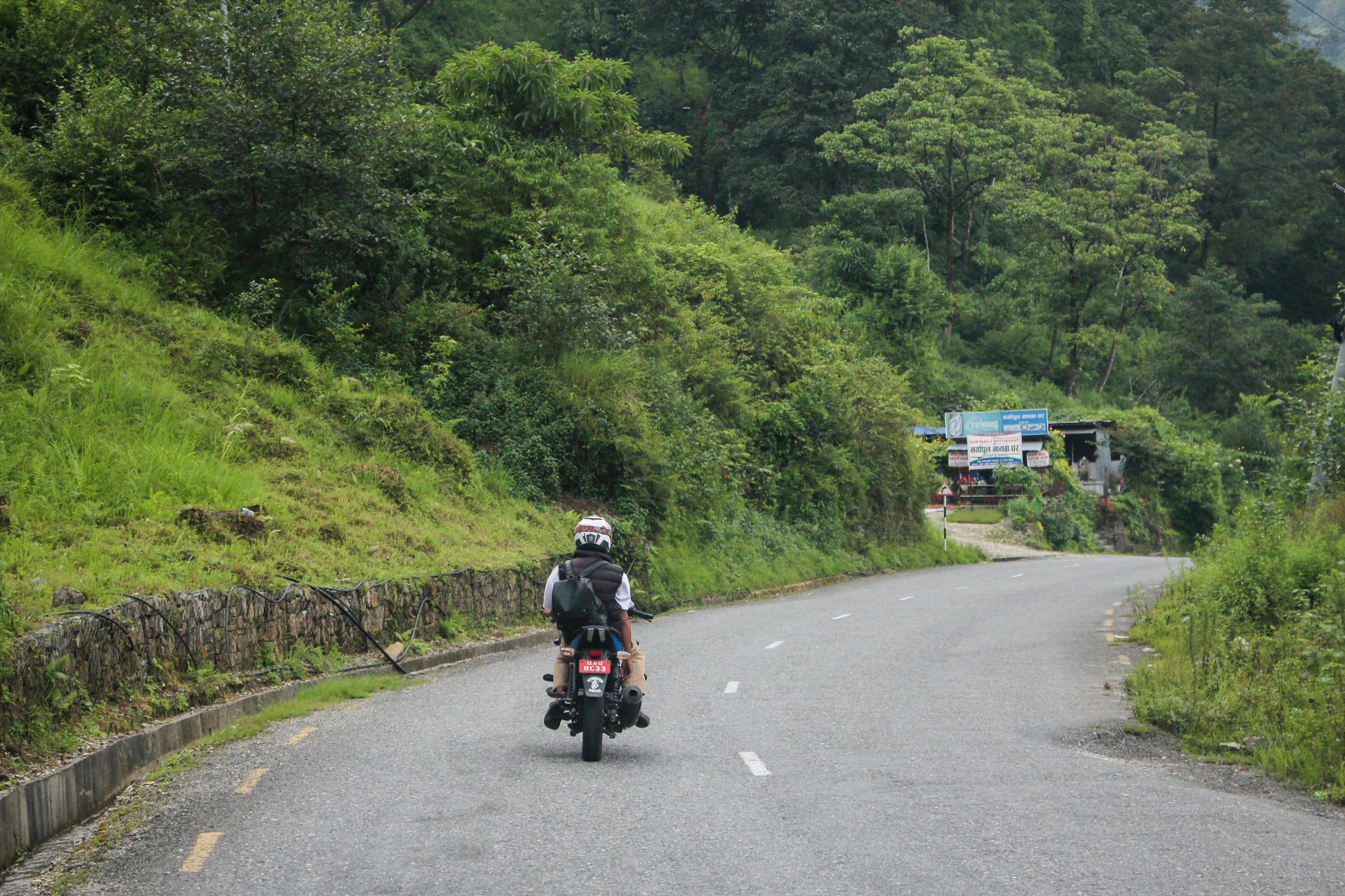 Man Riding Motorbike on Road in Green, Rural Scenery · Free Stock Photo