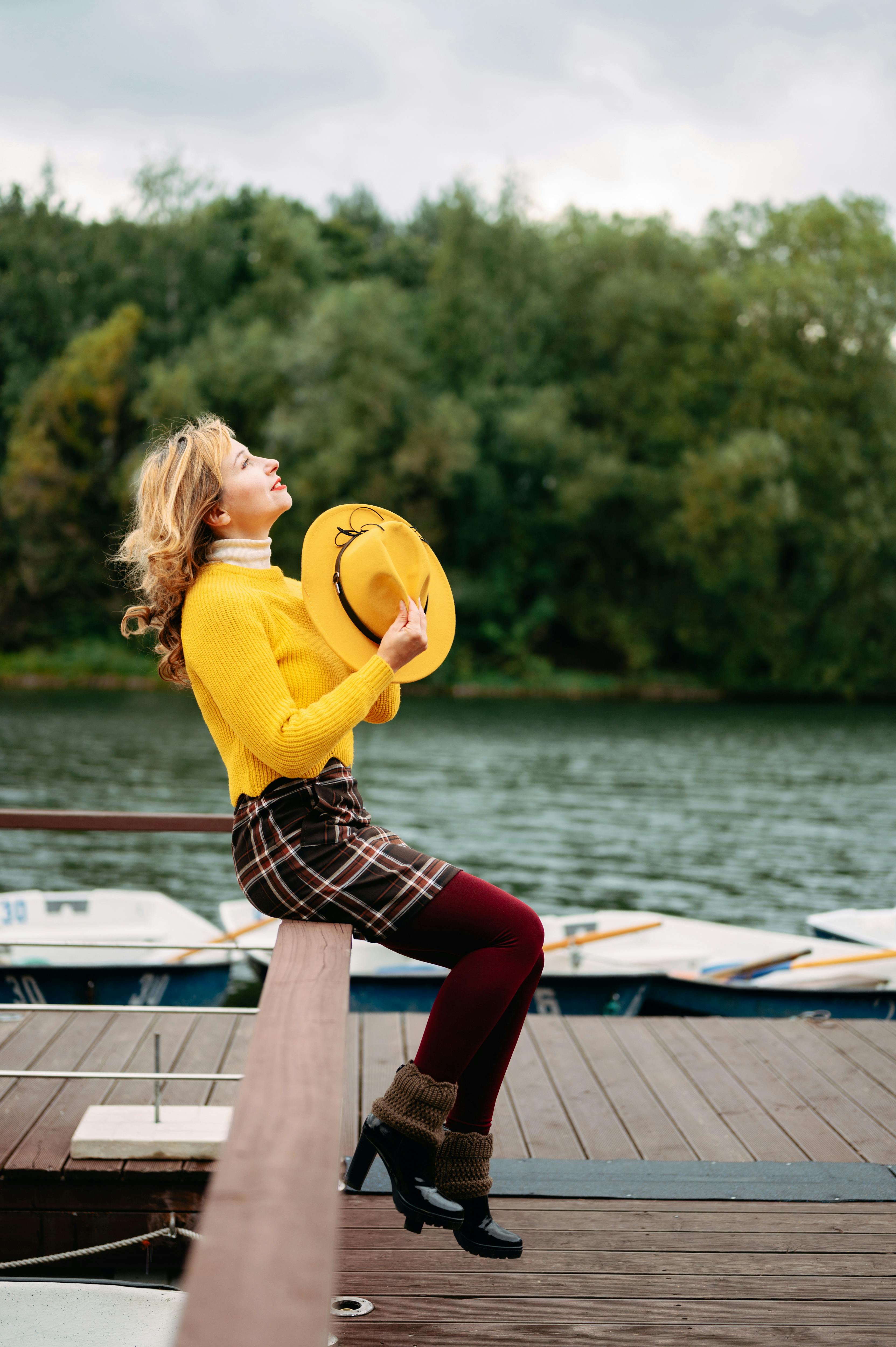 Woman in Yellow Sweater Sitting on Jetty Railing on Lake Shore · Free Stock Photo