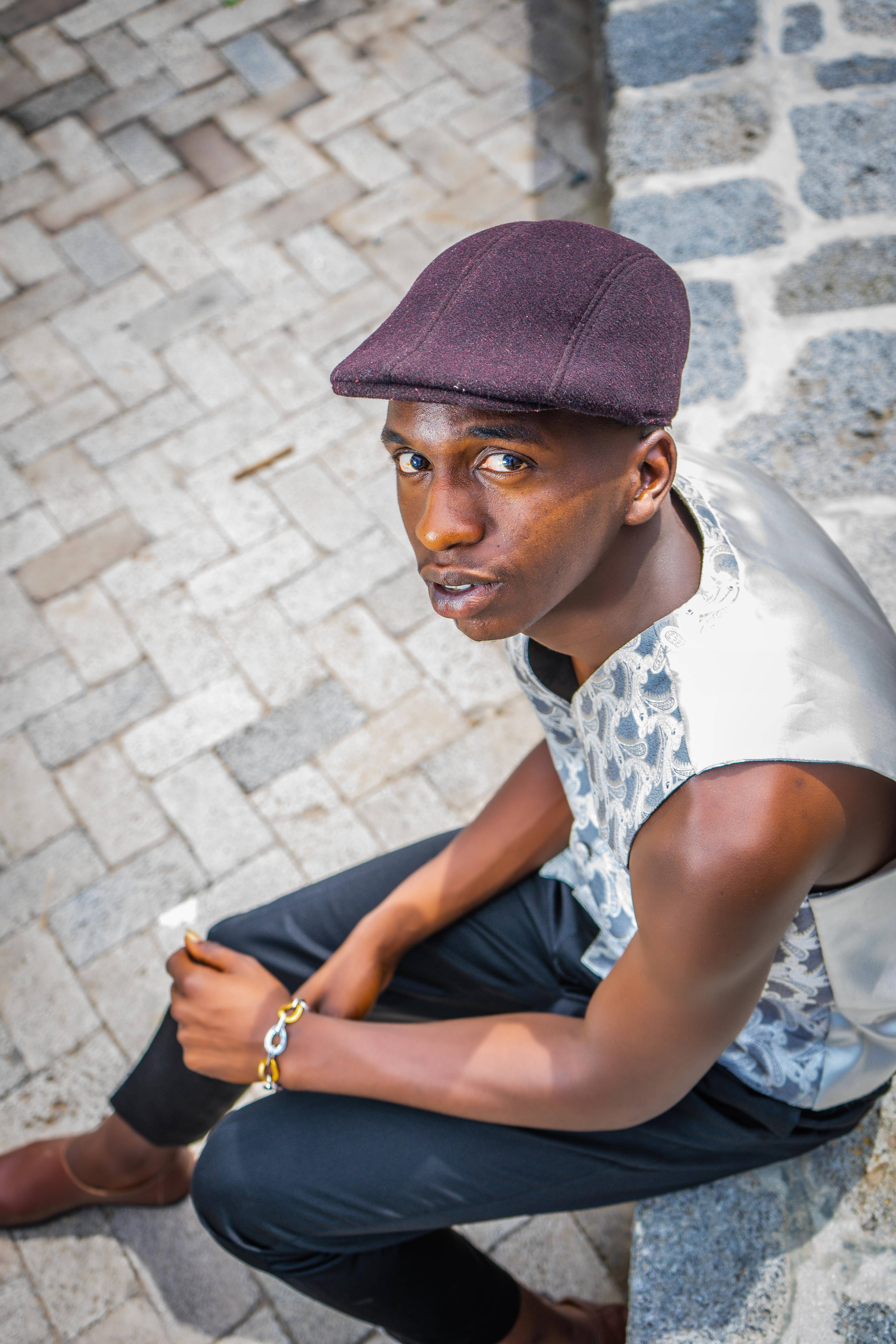 Man in Hat Sitting on Wall · Free Stock Photo