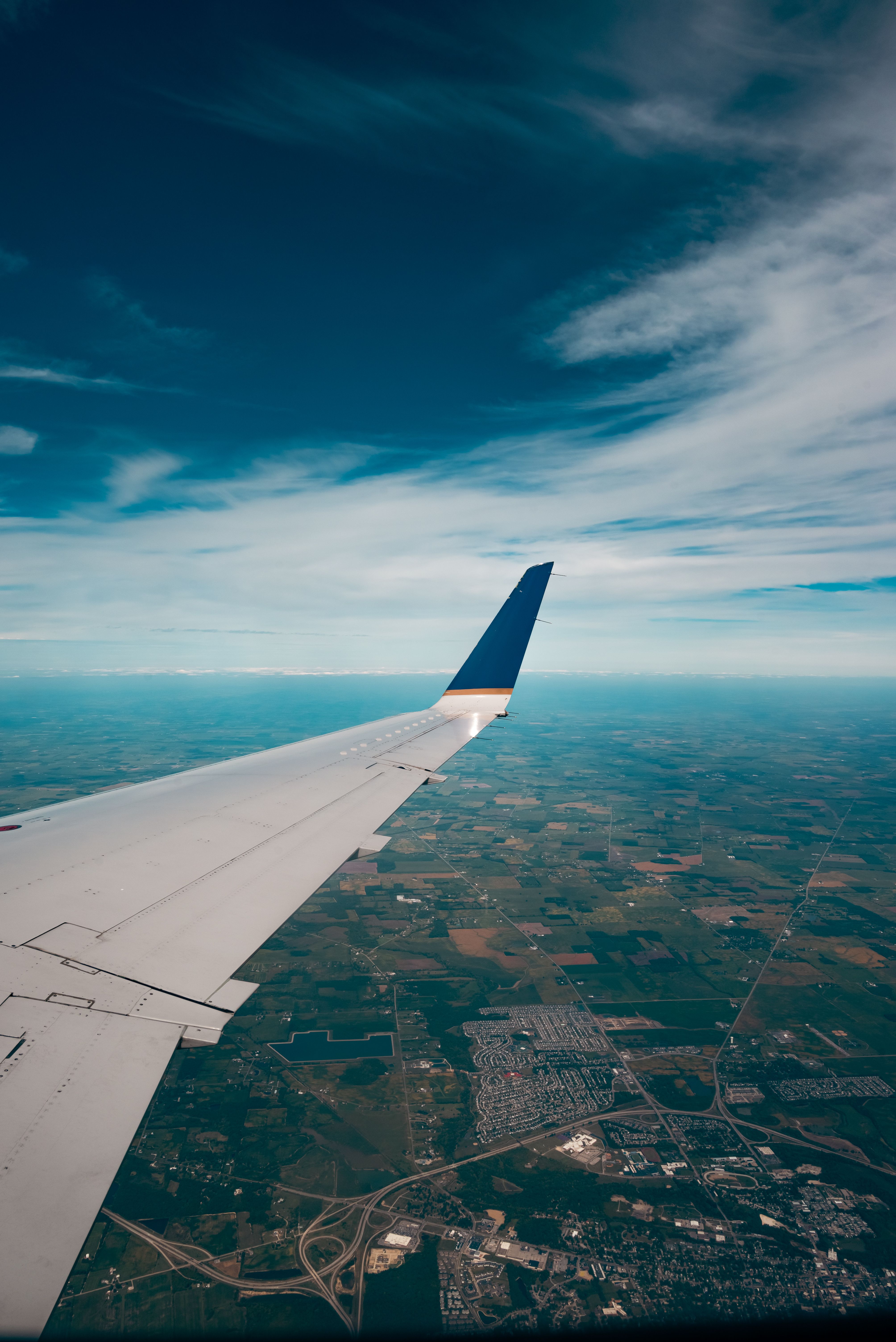 Wing of Airplane Flying over Plains with Town · Free Stock Photo