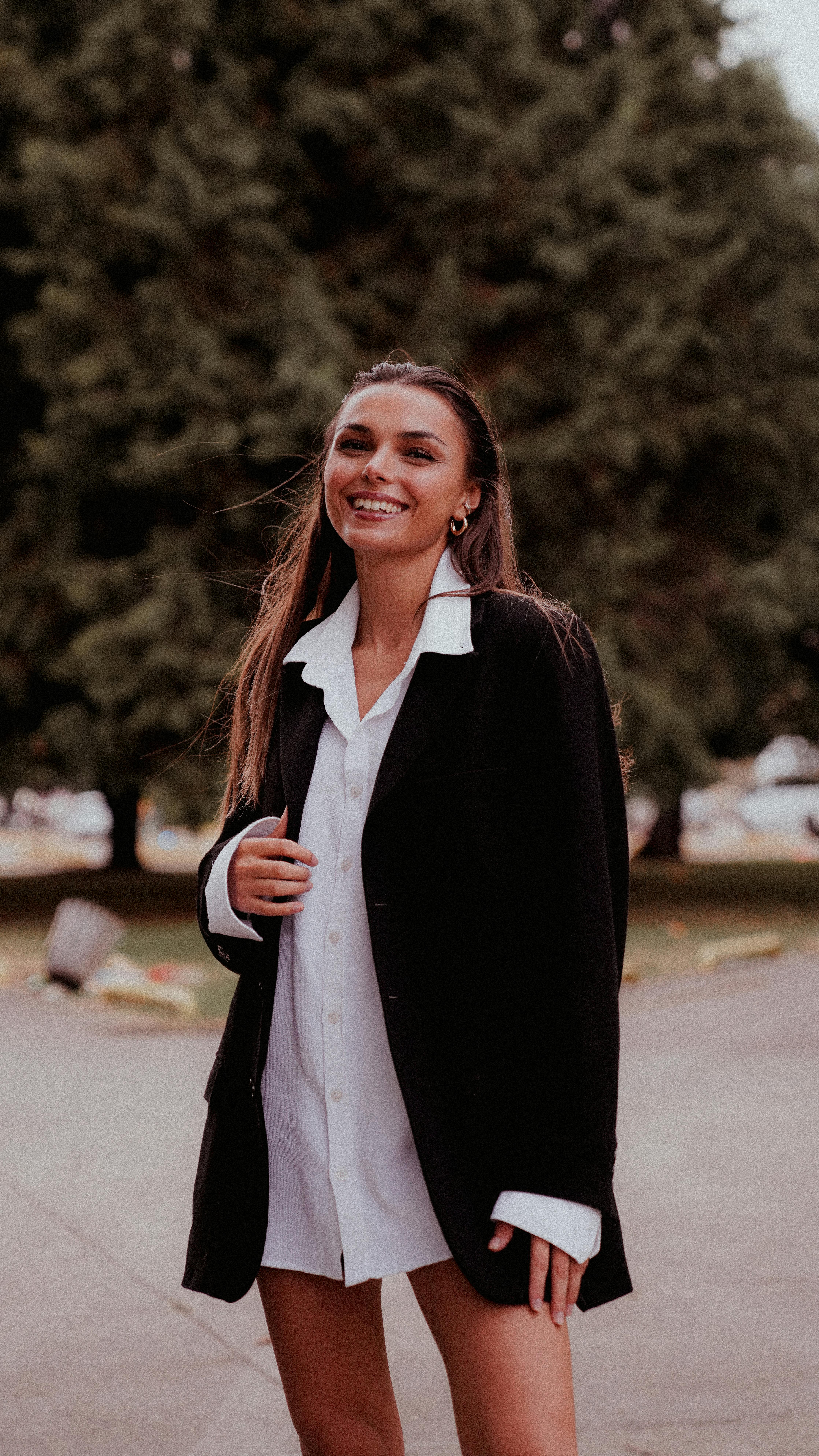 Smiling Young Model in a White Blazer Over a Beige Blouse Posing by the ...