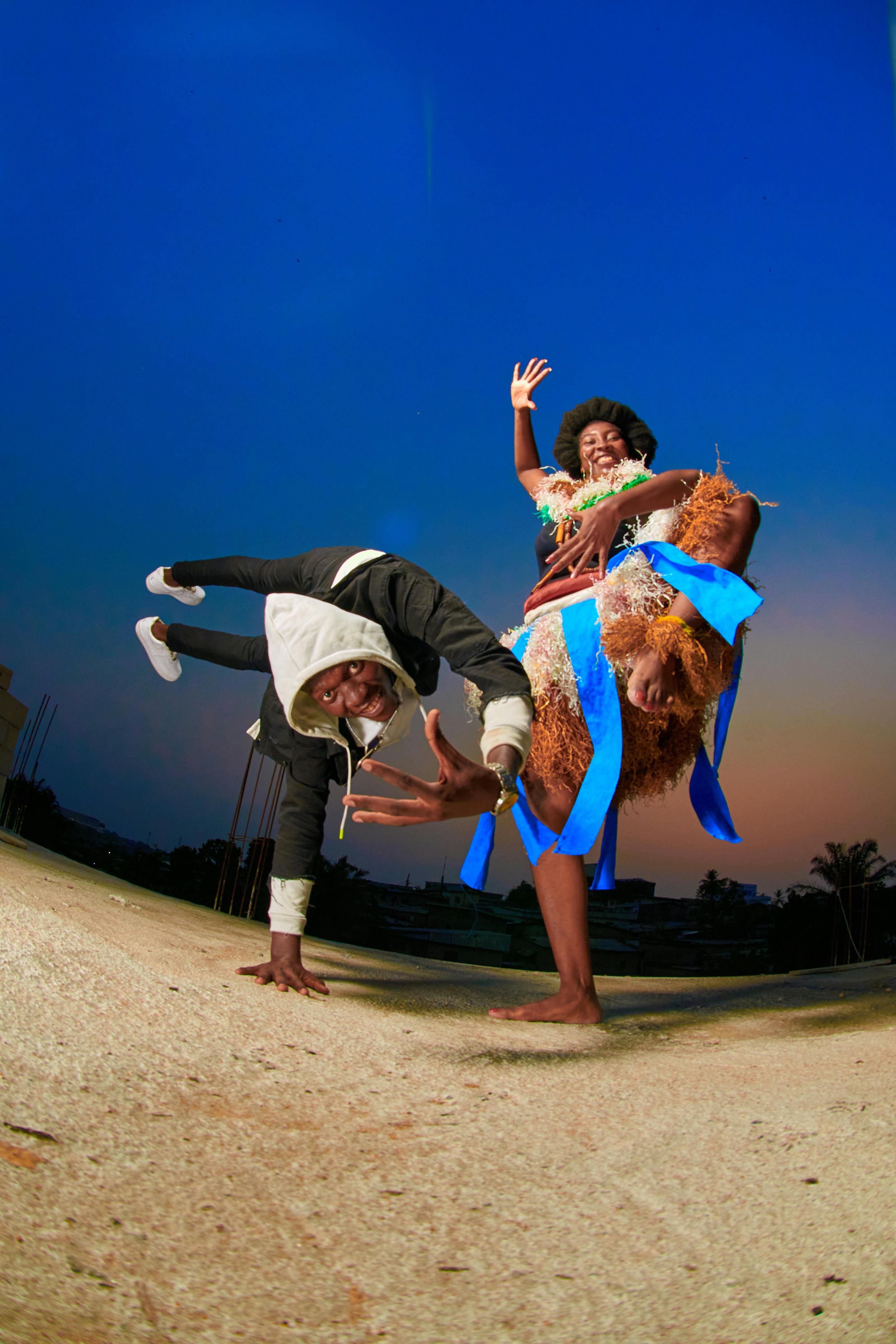 Man Breakdancing Next to a Dancer in Dry Grass Costume · Free Stock Photo
