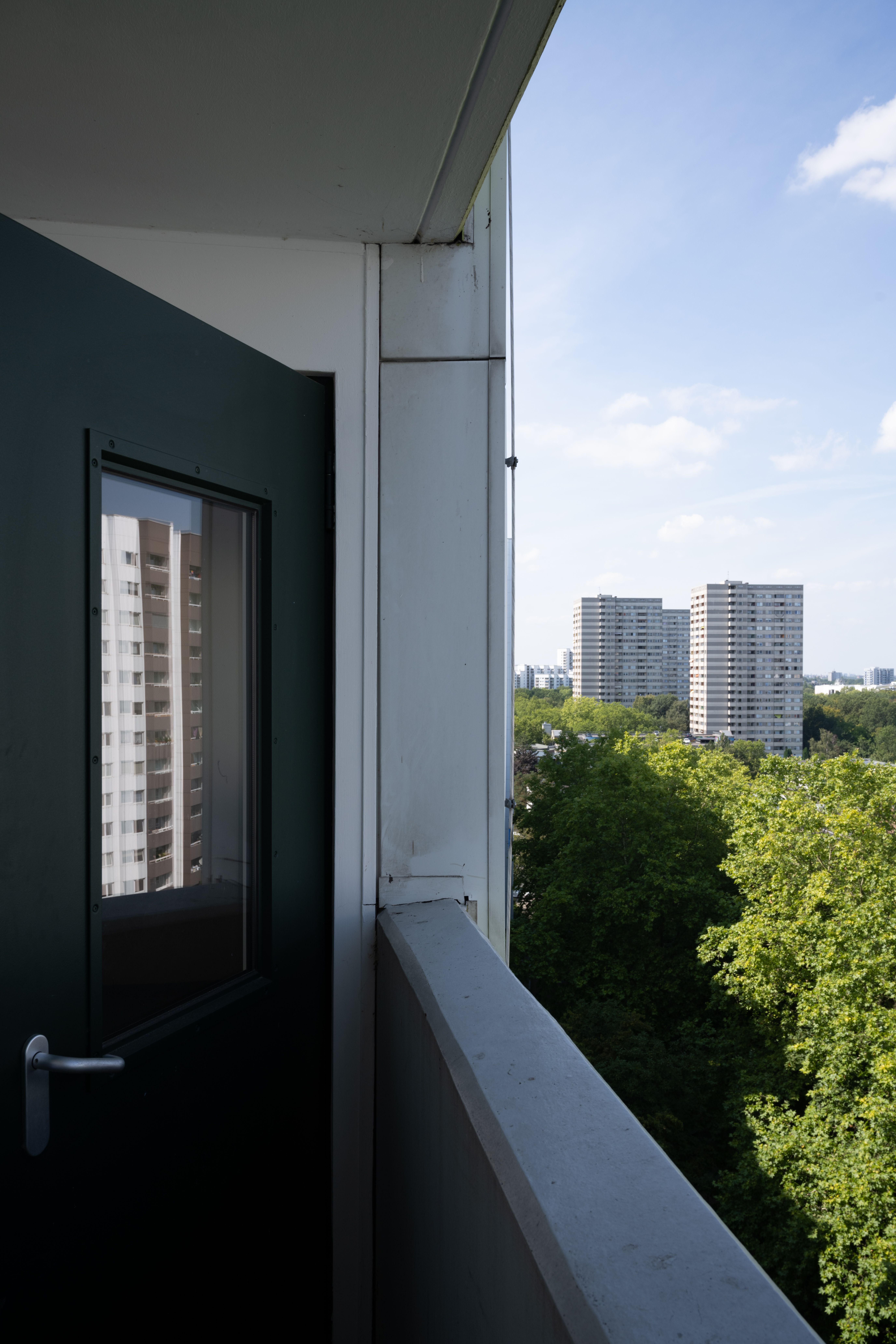 A view of a balcony with a green door and trees · Free Stock Photo