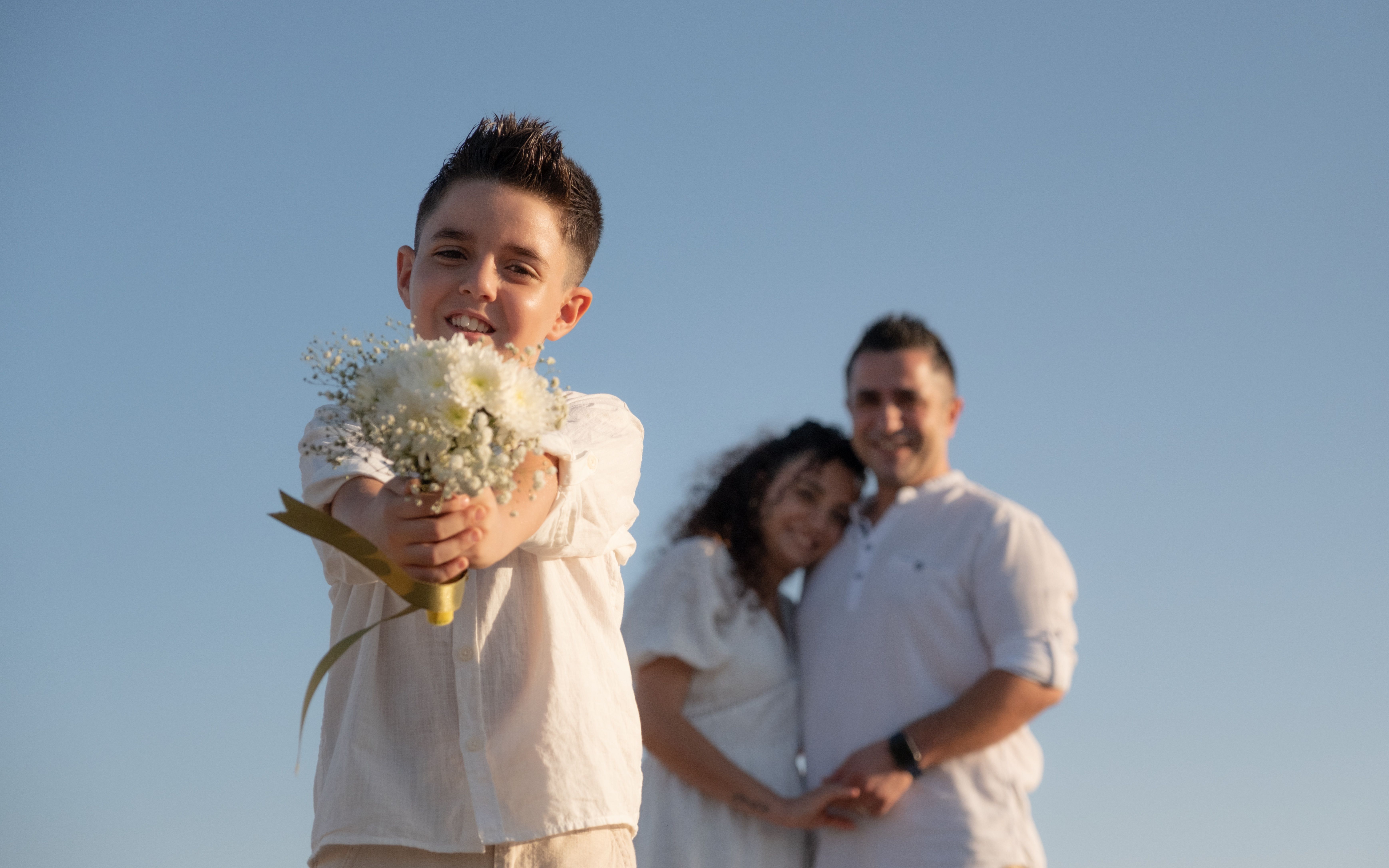 Smiling Boy with Bouquet of Flowers Standing in Front of Happy Couple ...