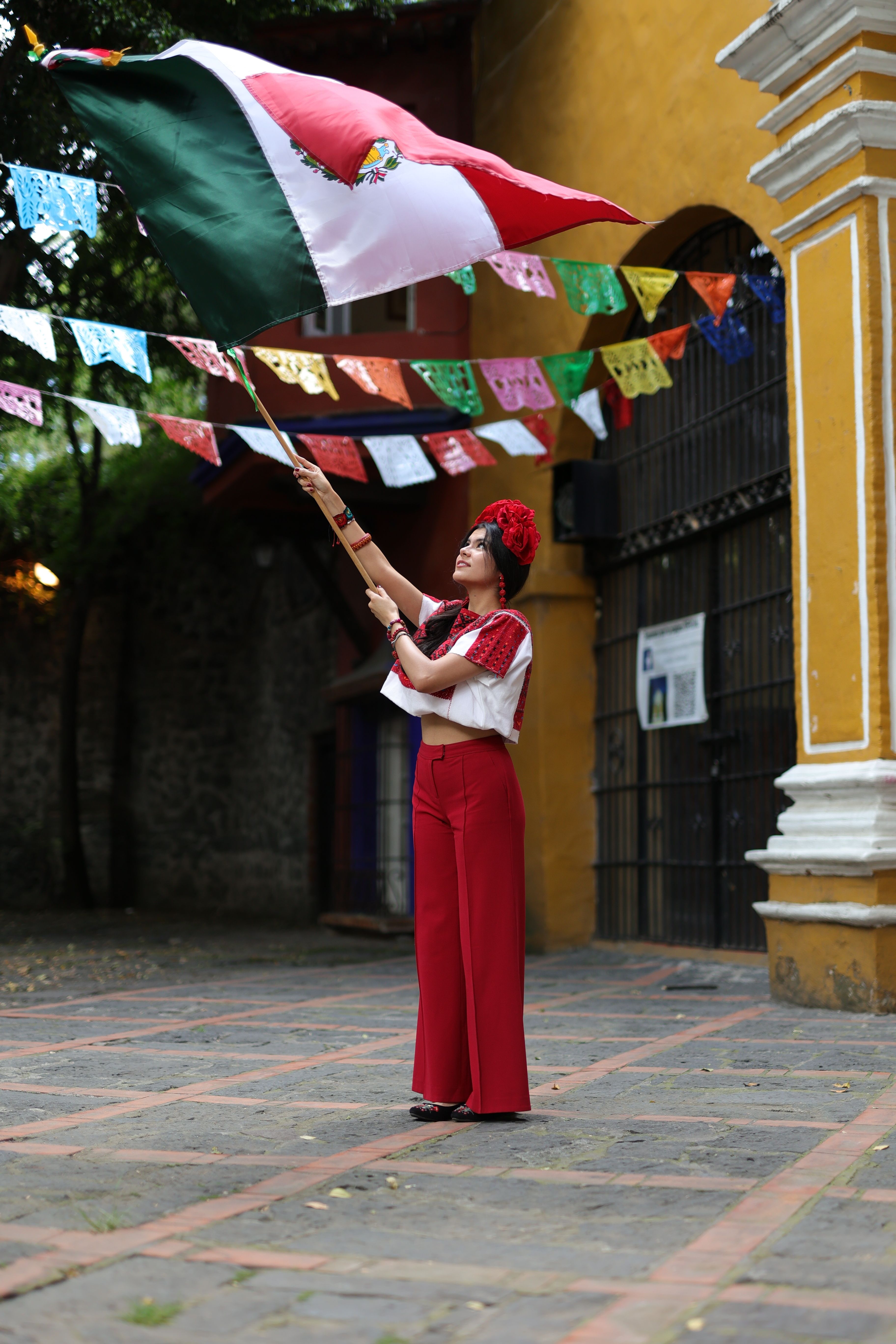 A woman holding a mexican flag in front of a building · Free Stock Photo