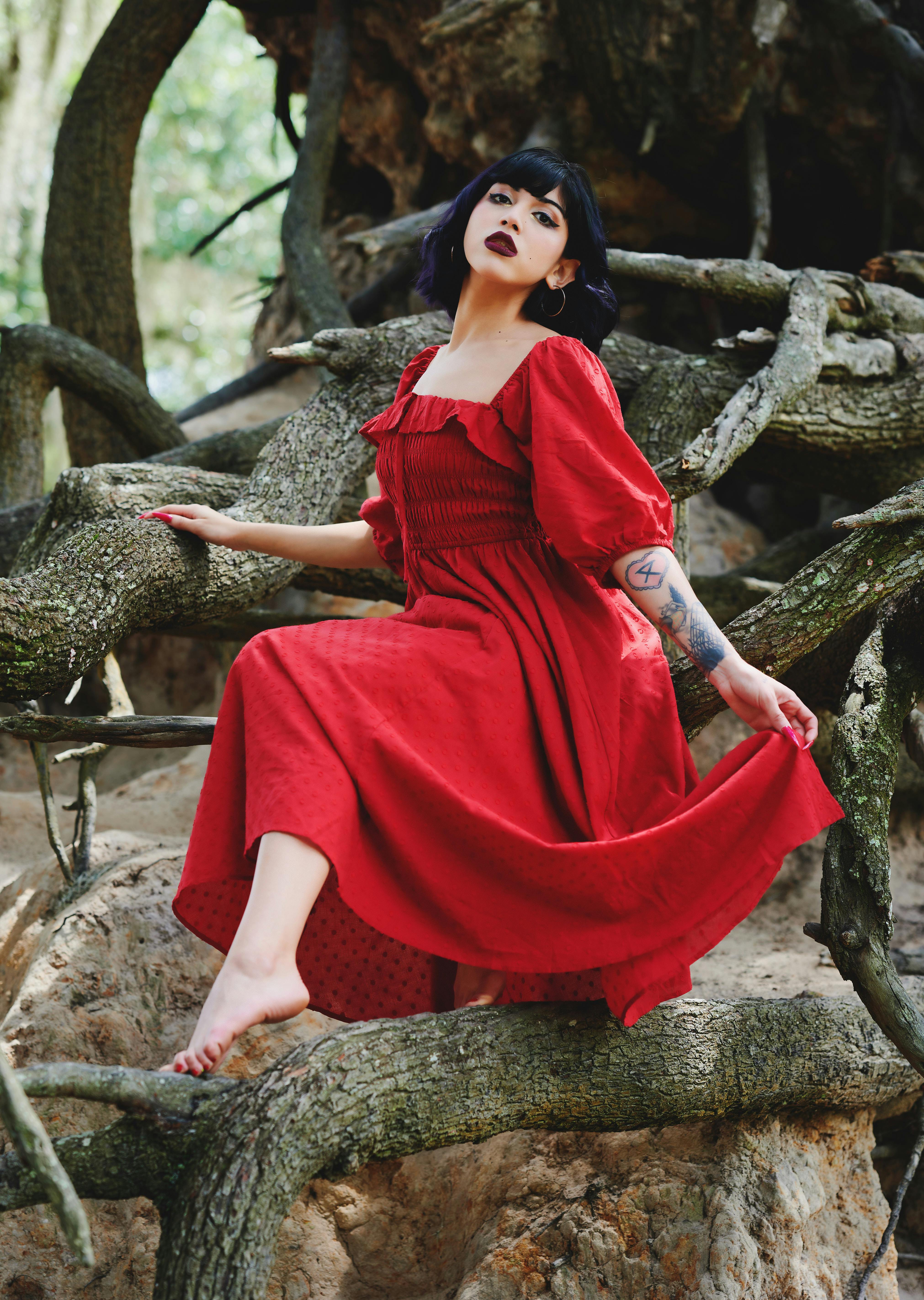 Young Woman in a Red Dress Sitting on Large Tree Roots · Free Stock Photo