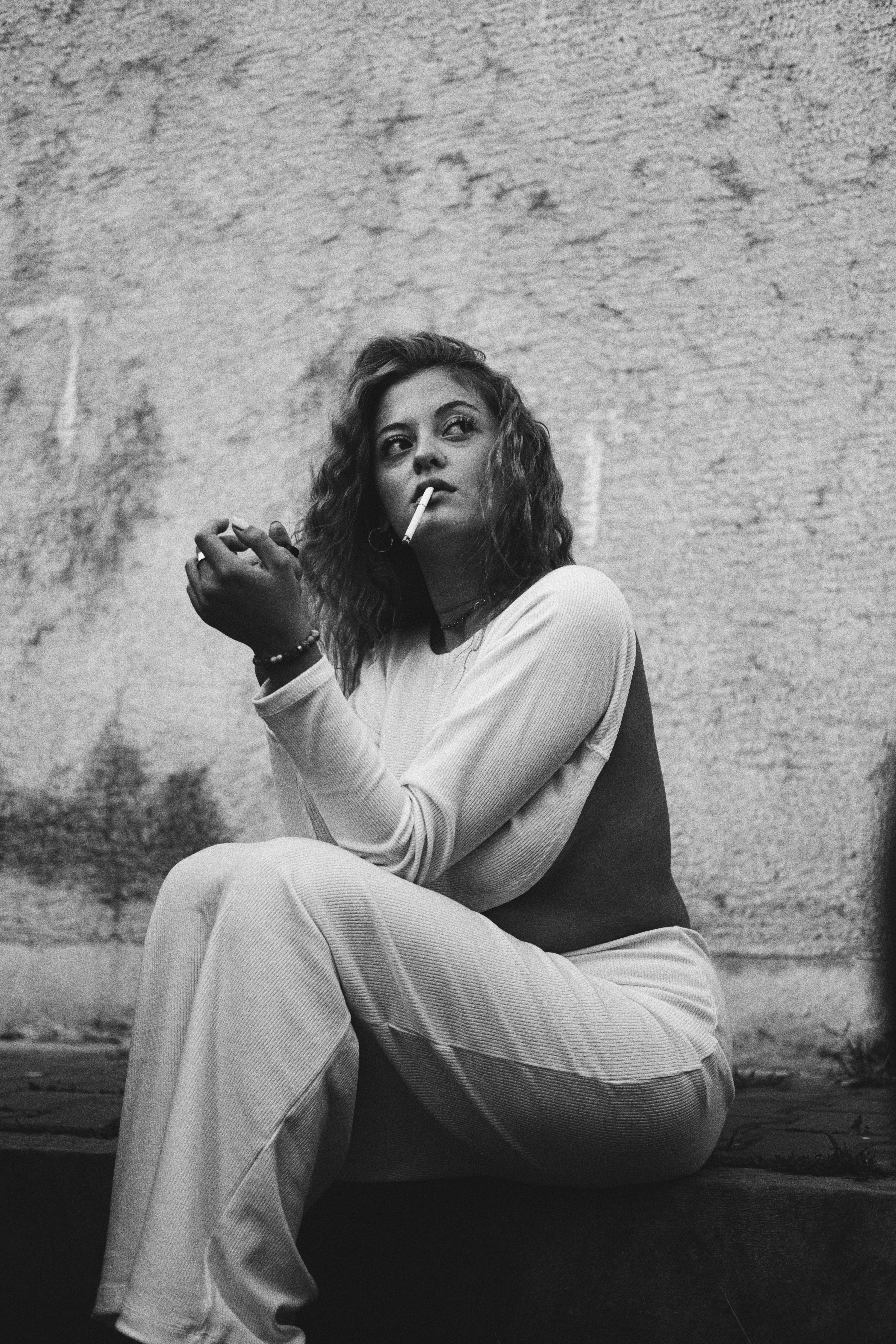 Woman in a Hat and Crop Top Smoking a Cigarette in the Back Alley ...