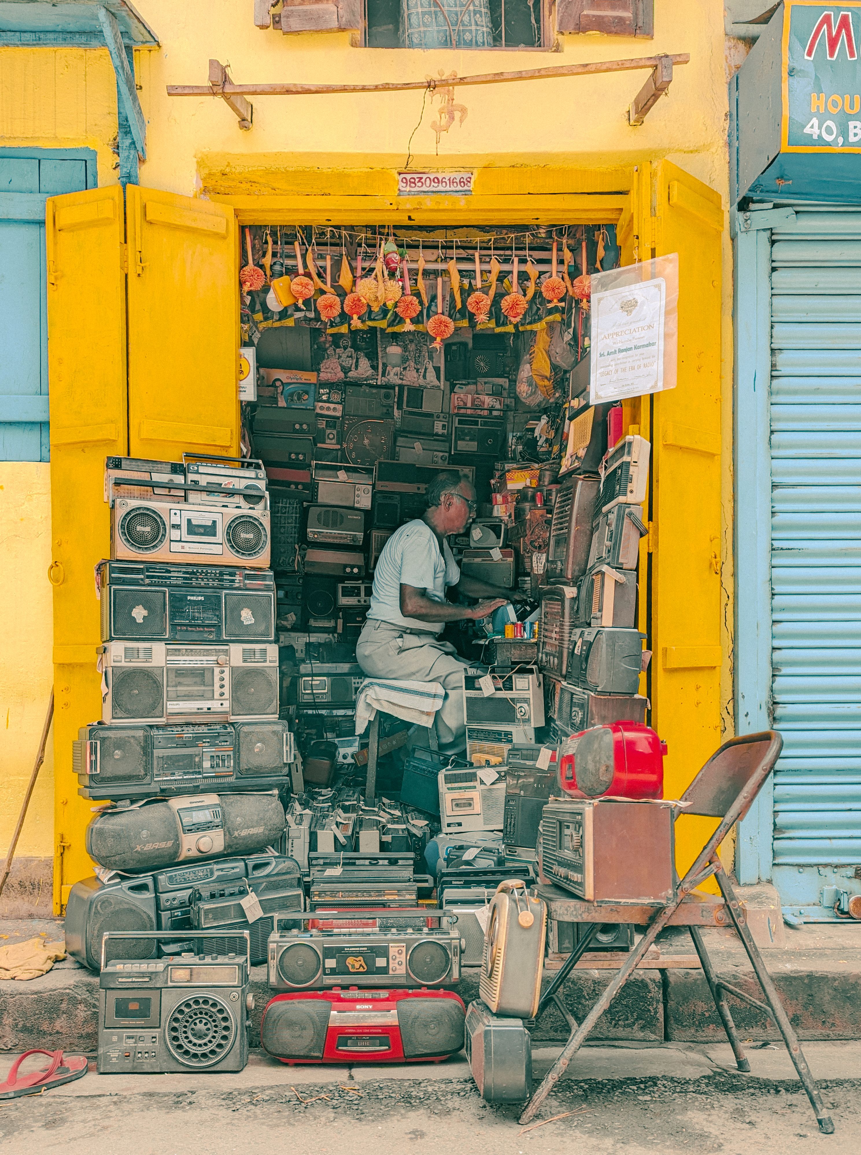 Man Sitting at an Electronics Shop with Stacks of Old Radios · Free ...