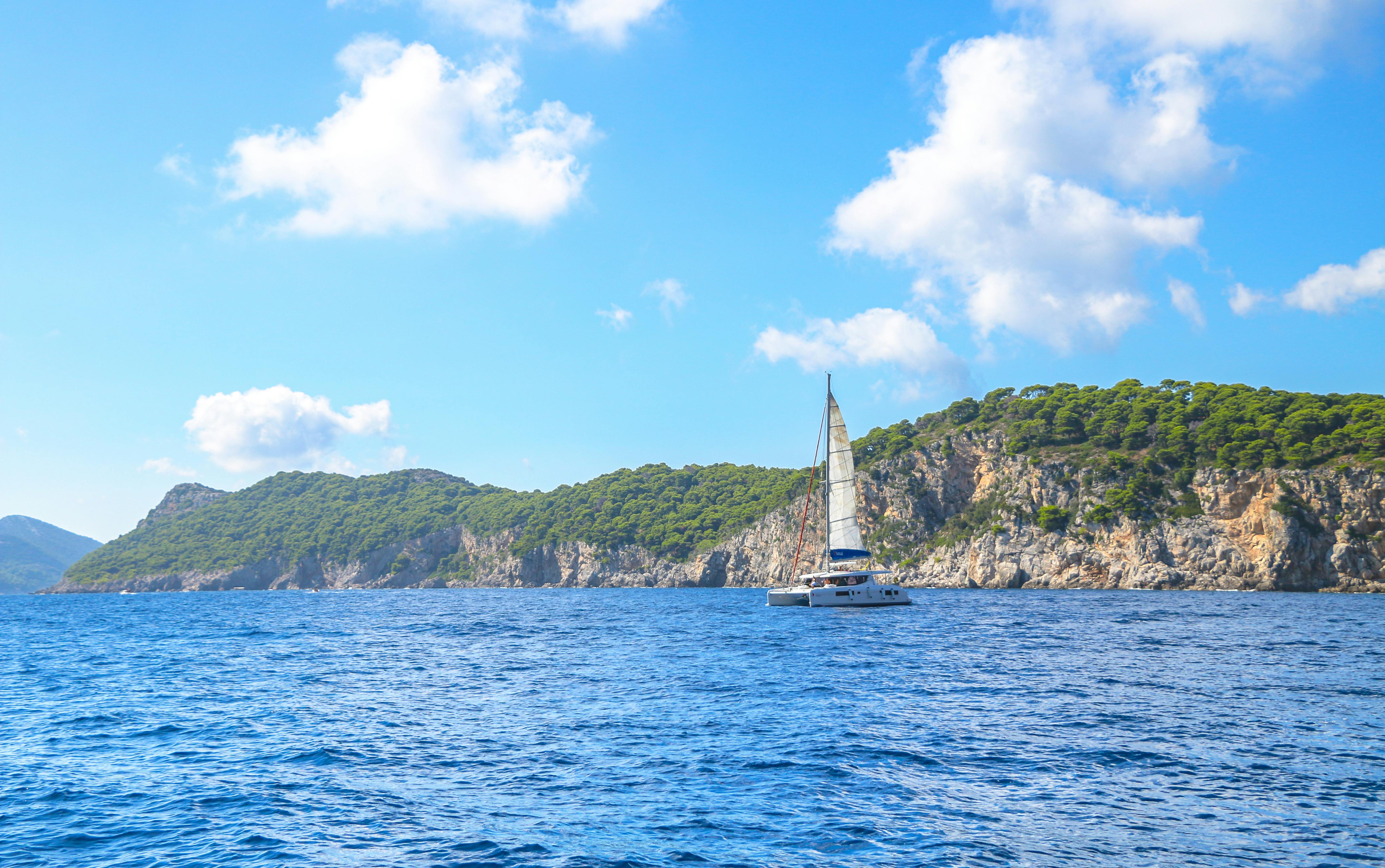 A Boat Sailing near a Coast with Cliffs · Free Stock Photo